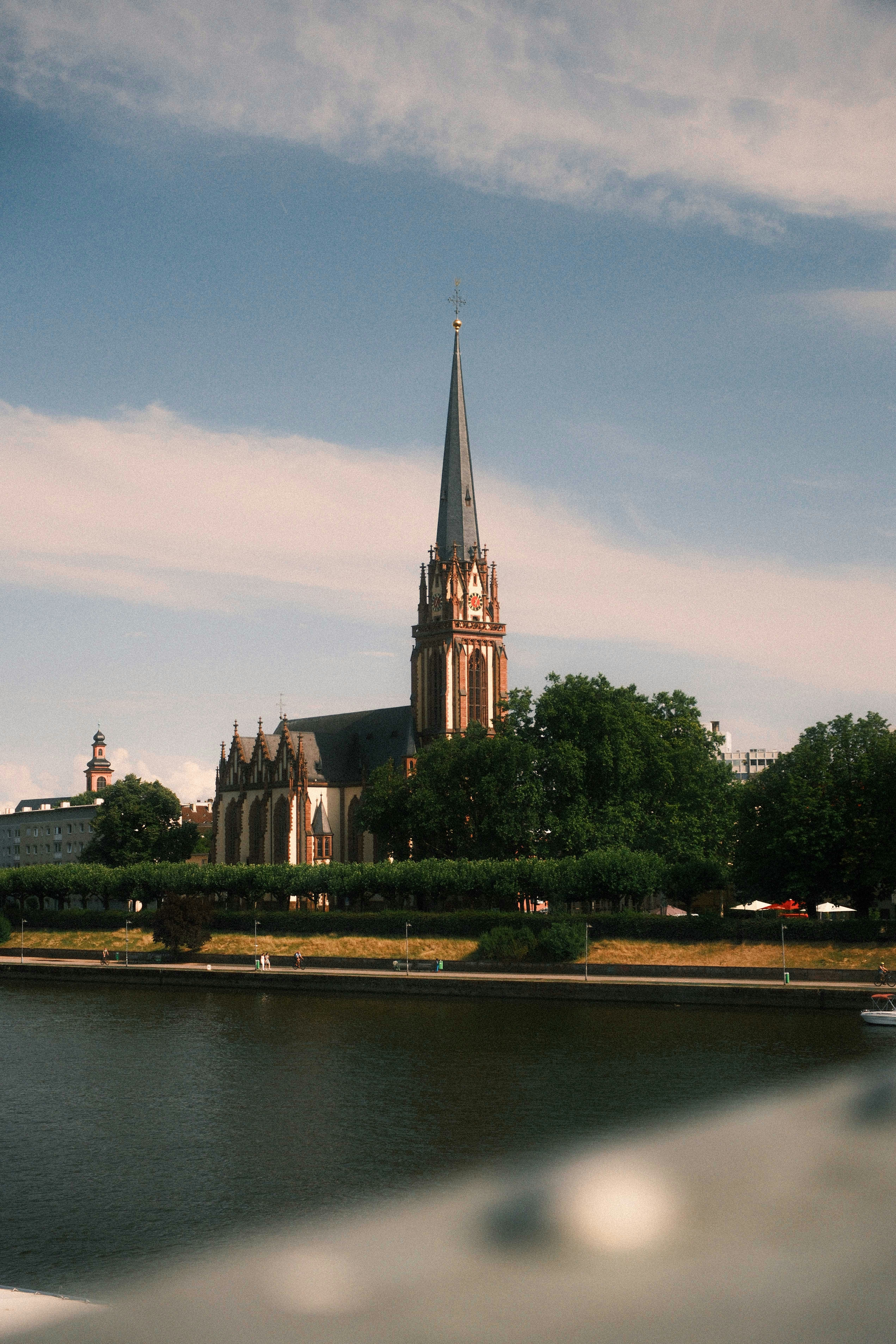 Spire Over the River: Gothic Cathedral Framed by Riverside Greens