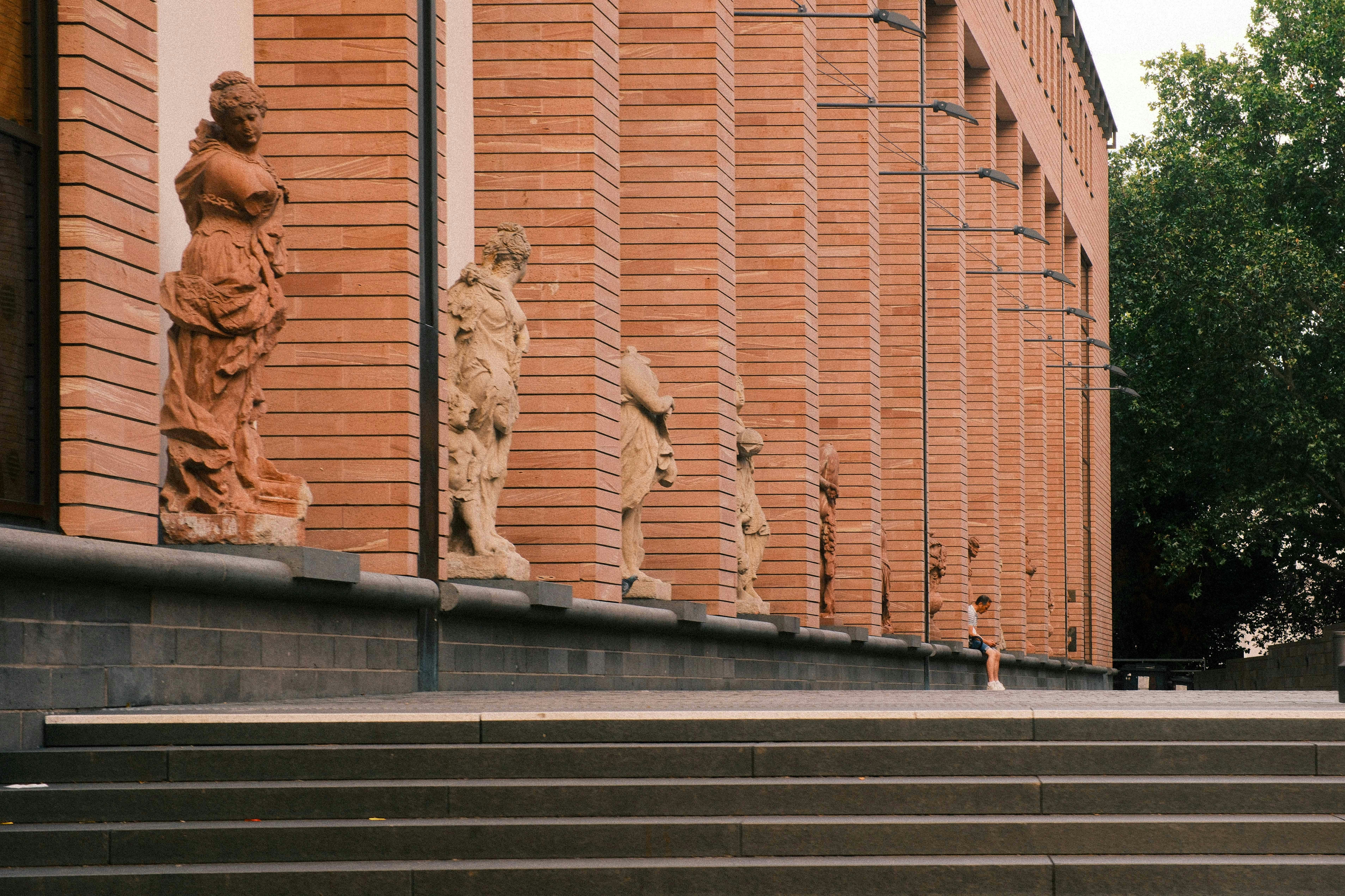 Red Brick Facade with Classical Statues and Shallow Steps