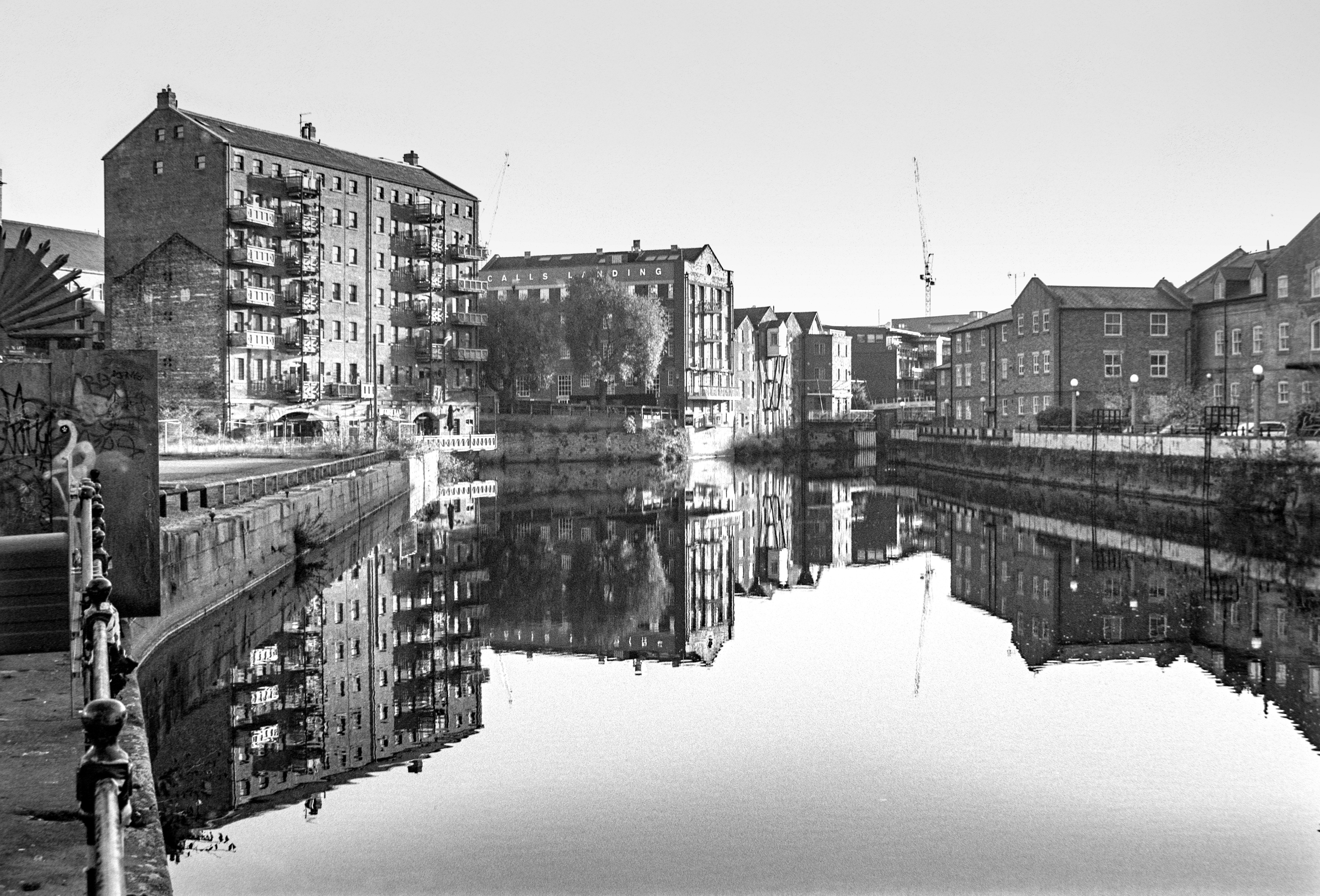 Former industrial buildings reflected in the River Aire in Leeds. Ilford Delta 100 film.