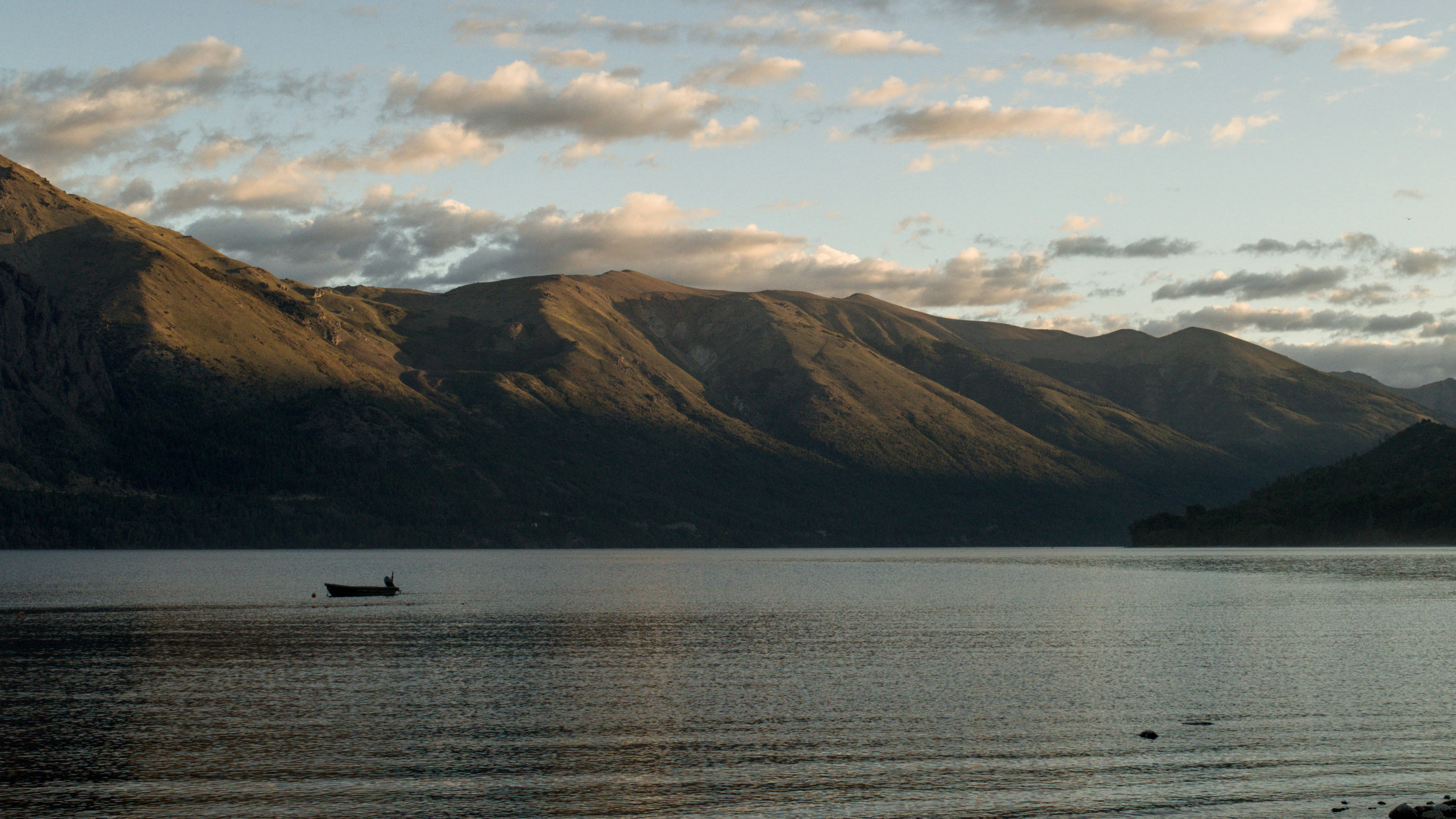 Quiet Fjord at Dusk: A Lone Boat and Shadowed Peaks