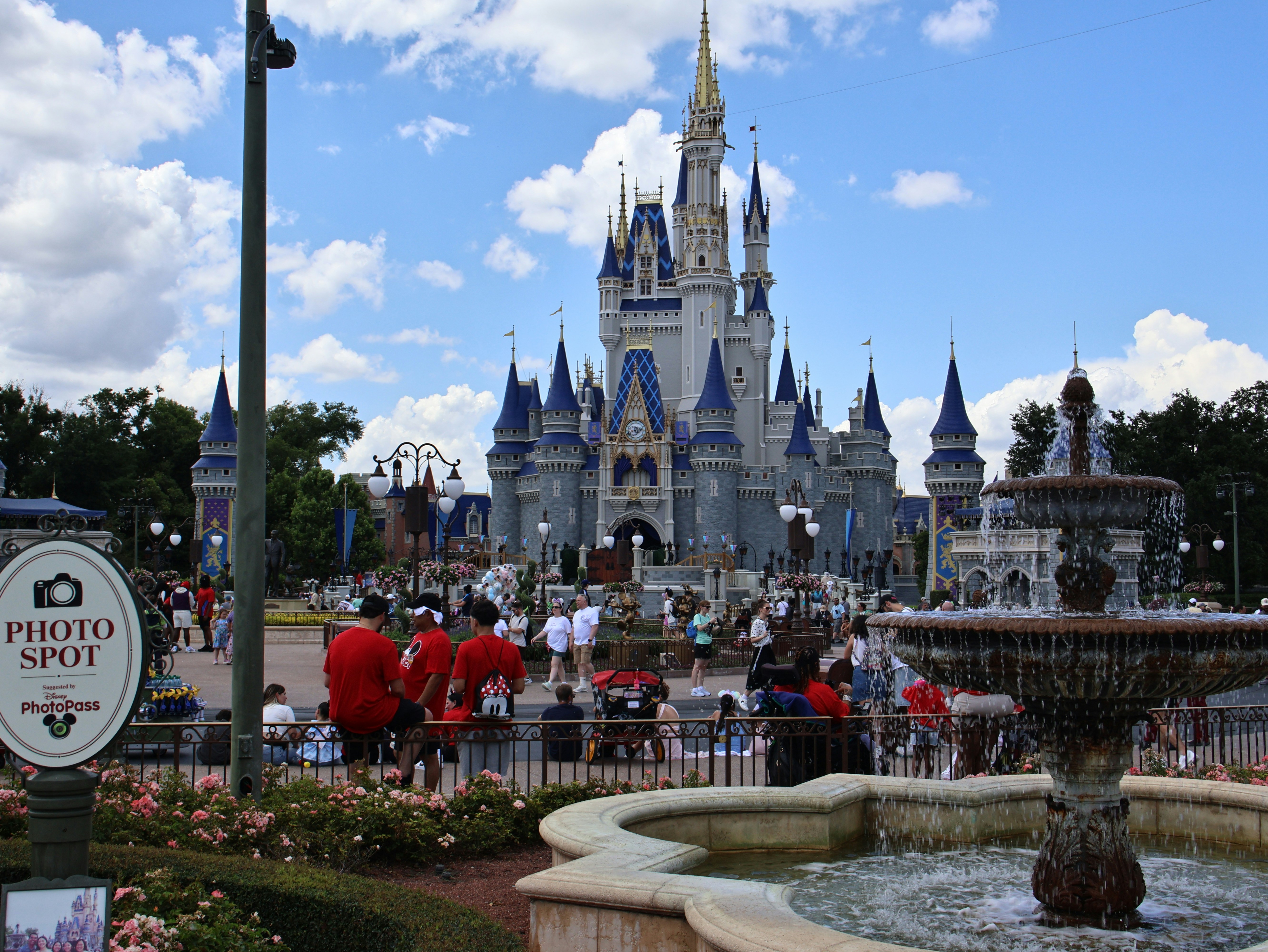 Castlefront Crowd: A Disney Castle framed by fountains and visitors