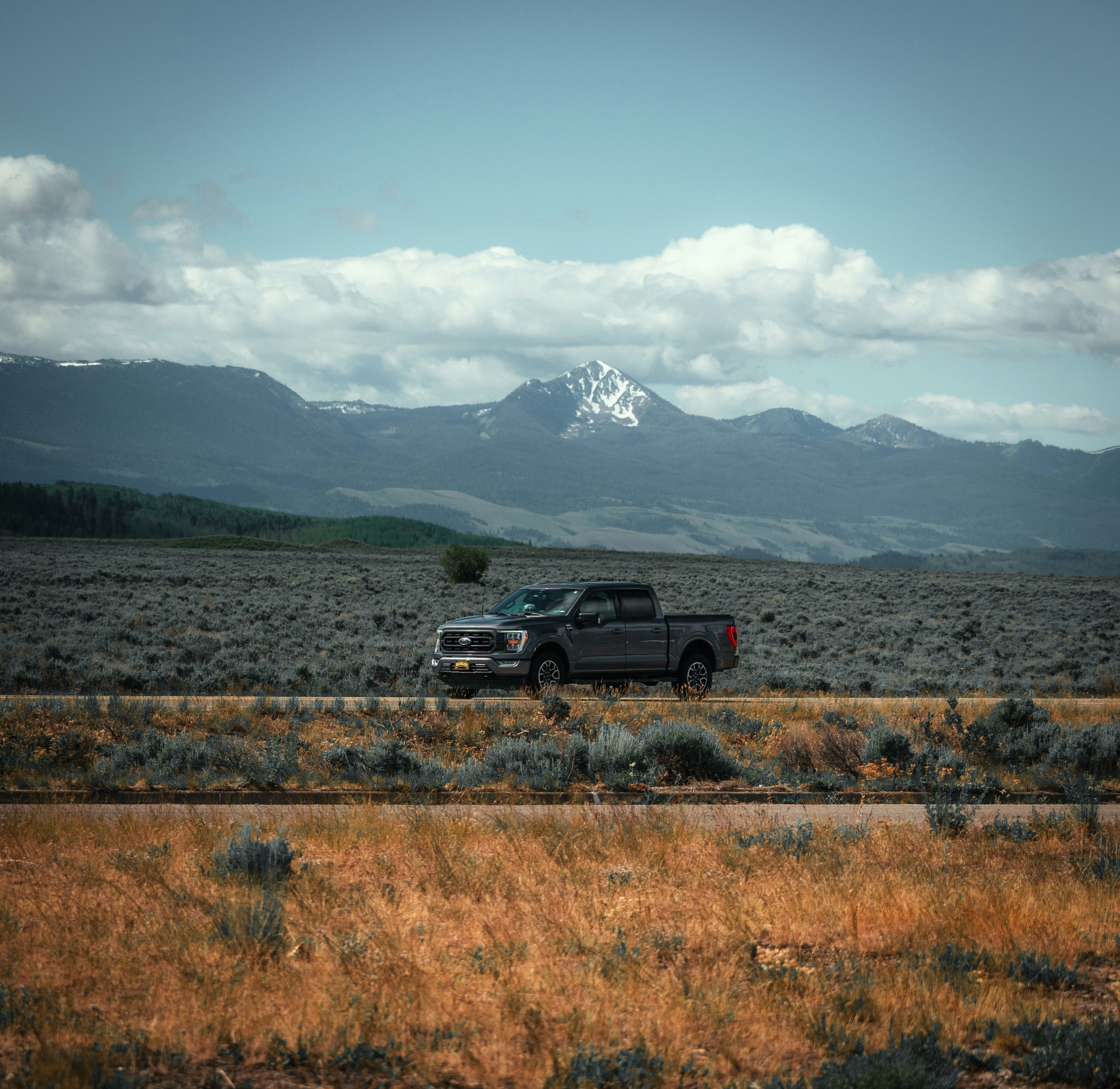 Mid-Desert Lift: A Dark Pickup Across the Sagebrush Plains Under Alpine Skies