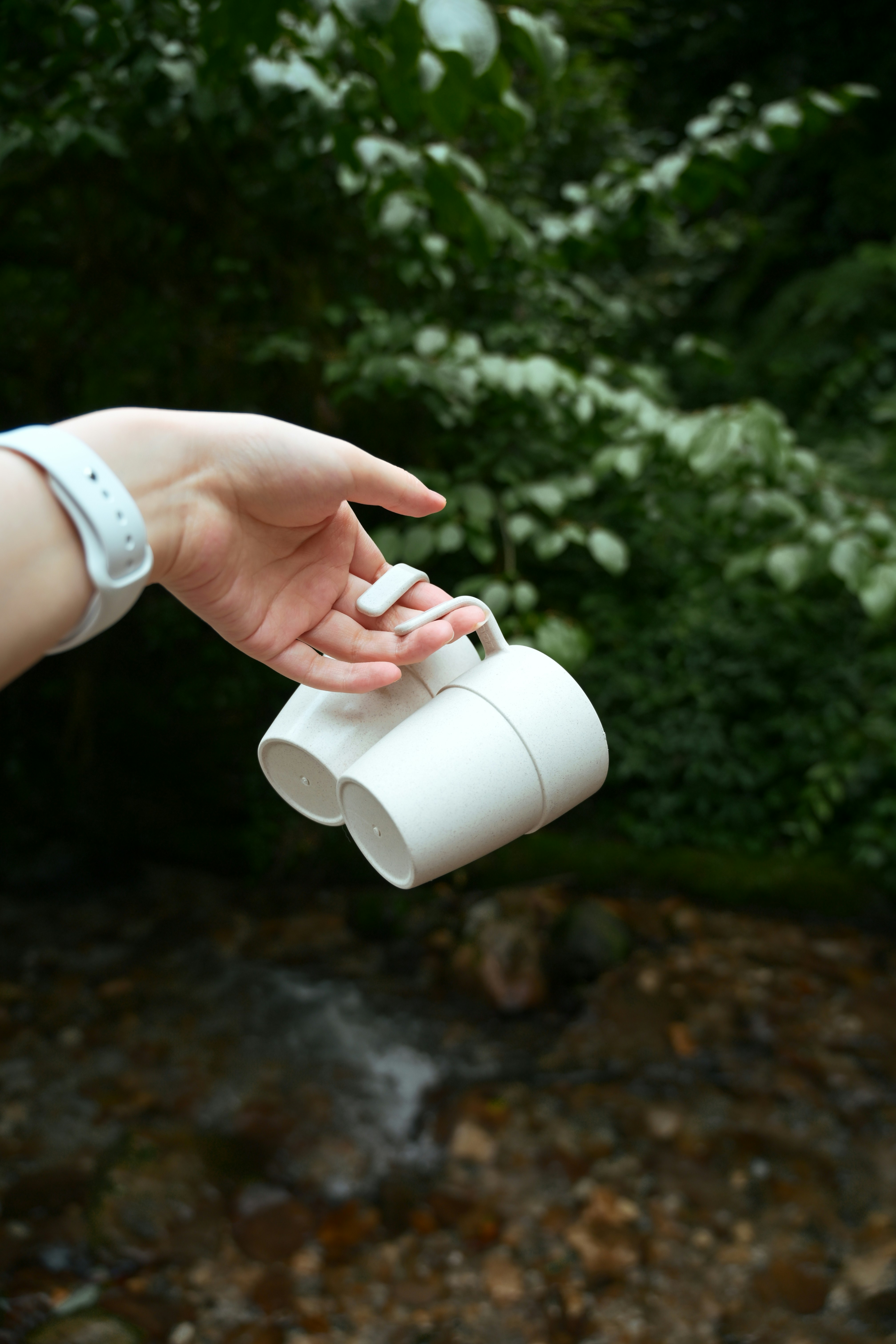 White cup handoff over a forest stream