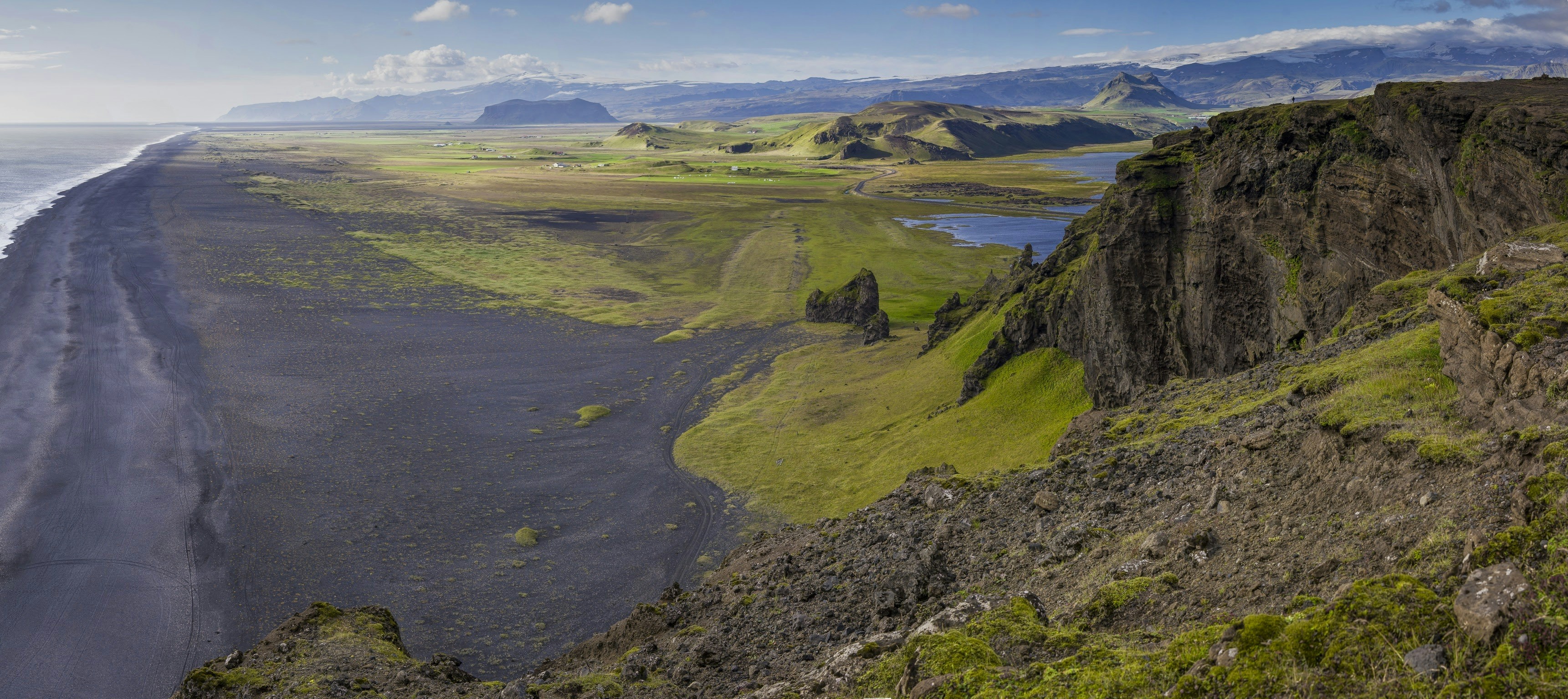 Lava-streaked coastline: green valleys meeting dark volcanic shore