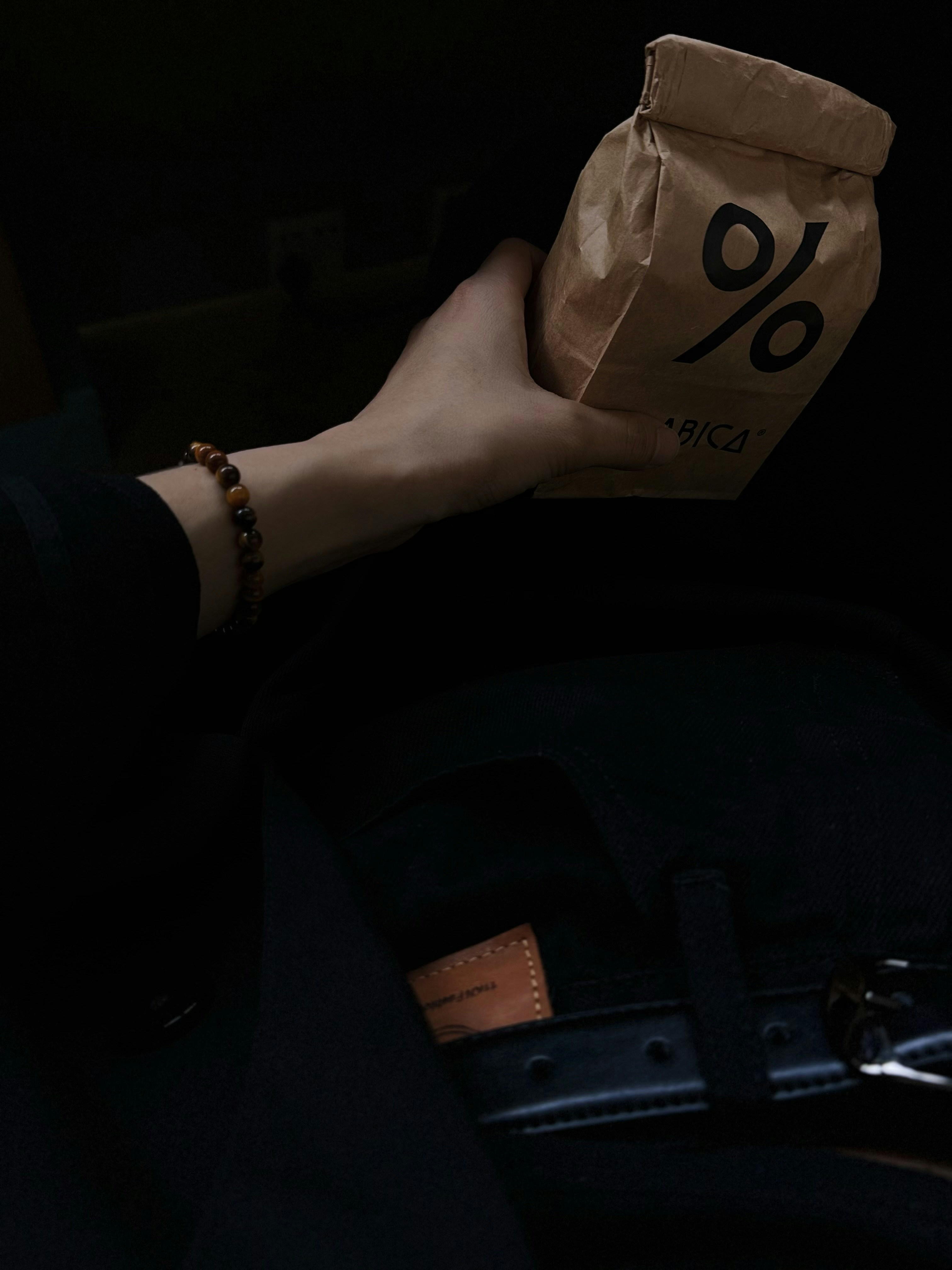 Dim Treasury: A hand clutches a bag with a bold percentage sign in a shadowed scene