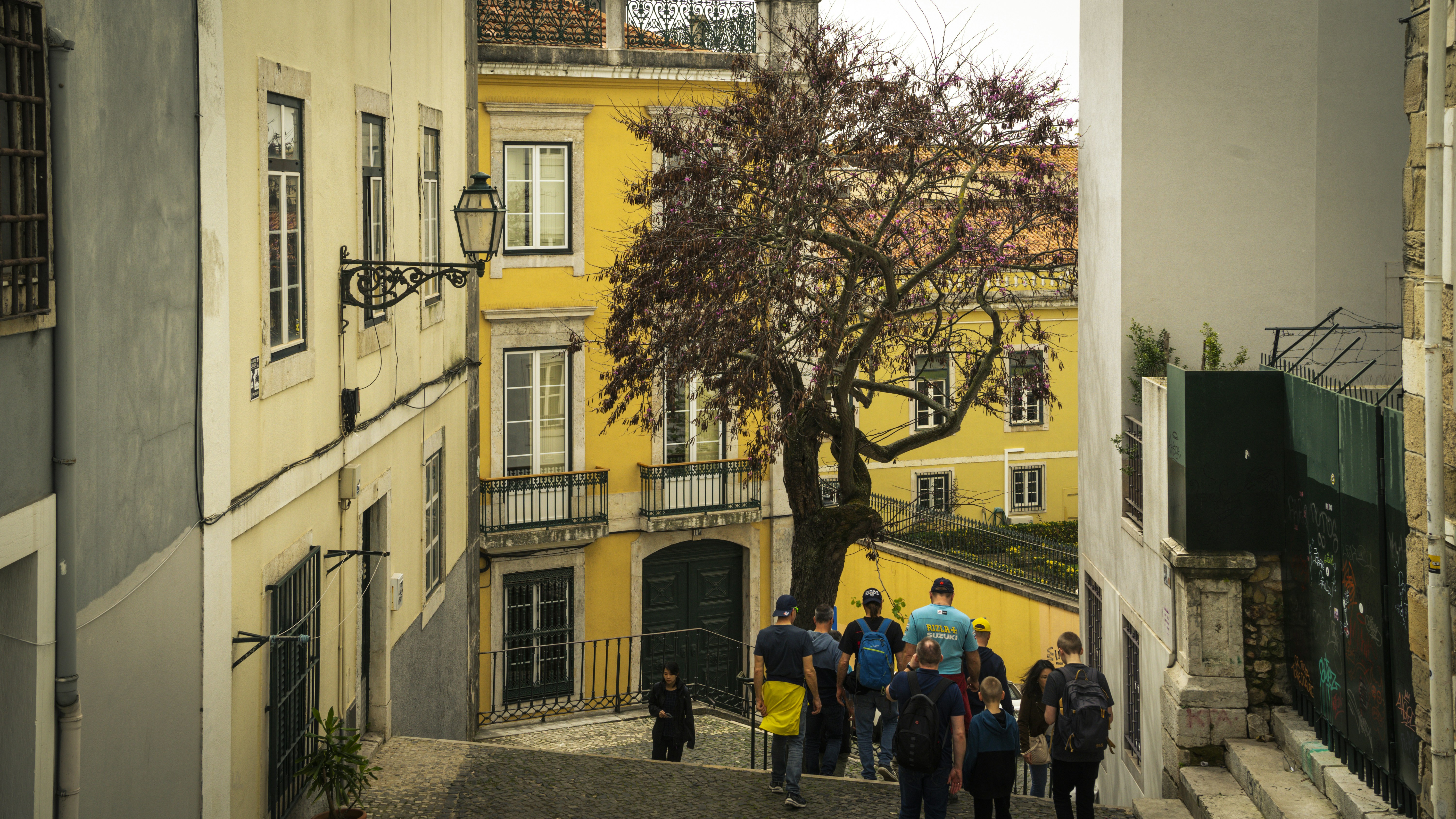 Up the Quiet Hill: Group of Friends Climb Past a Sunlit European Staircase
