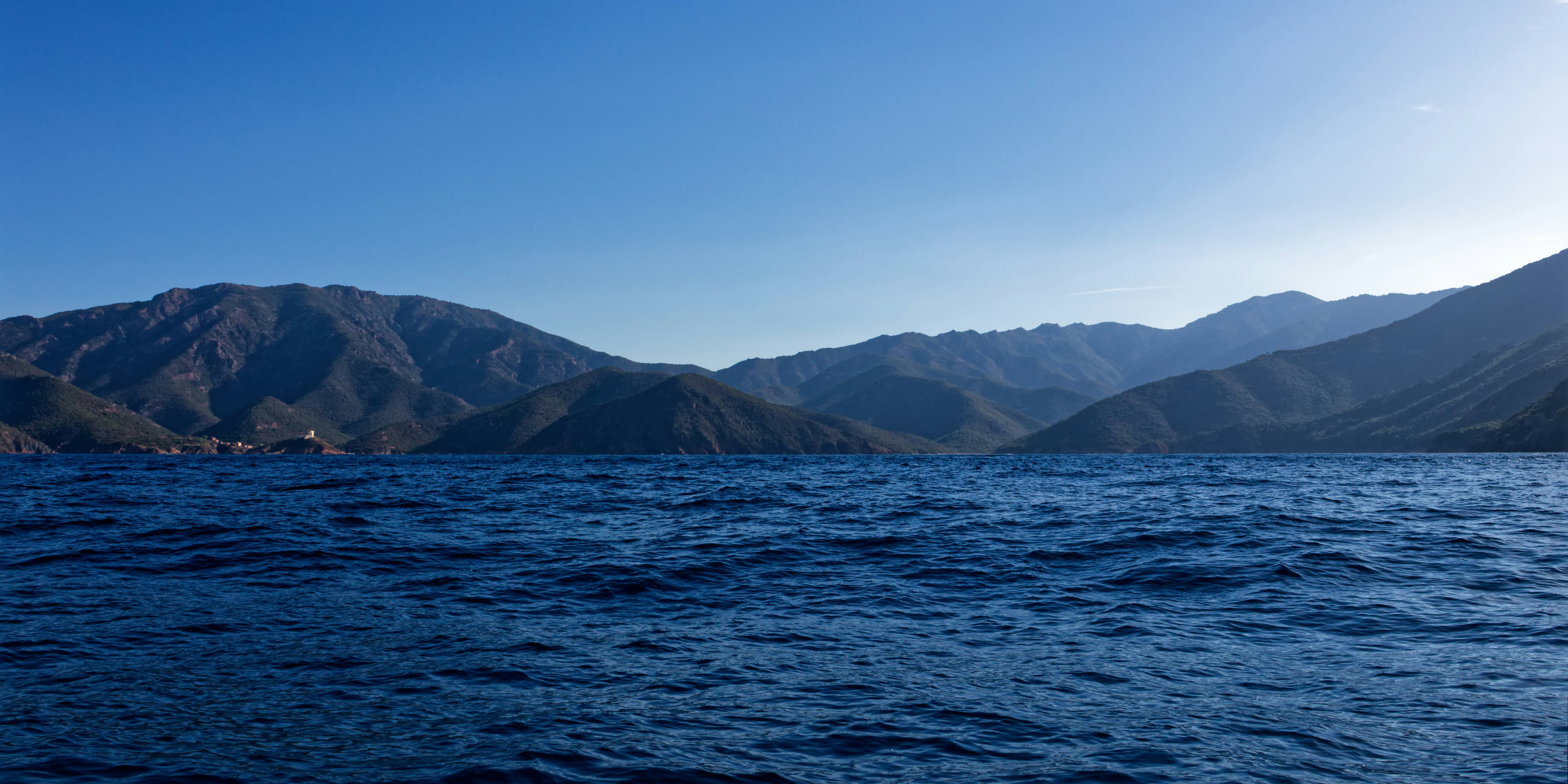 Distant Mountains Meet a Velvet Sea Under a Clear Blue Sky