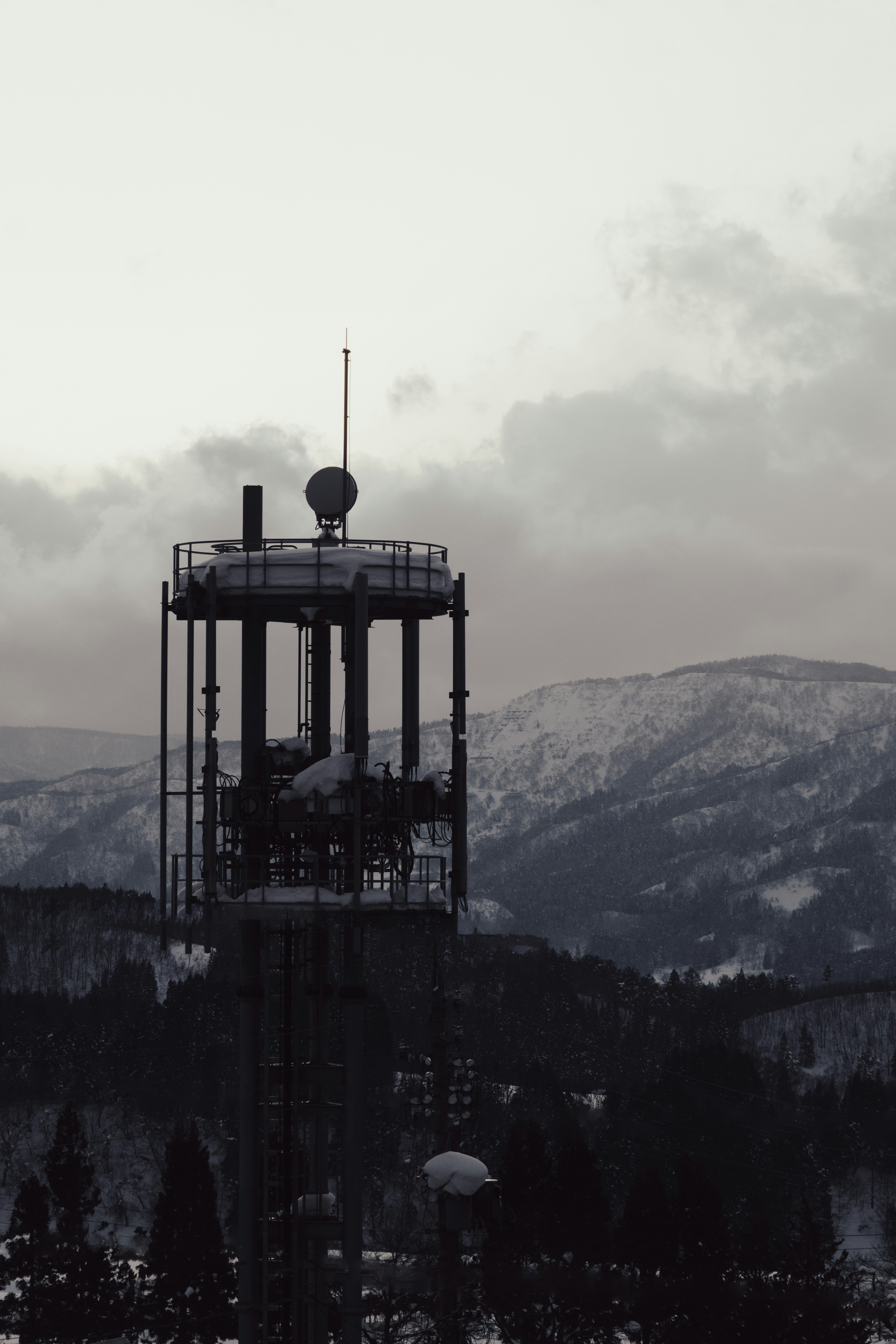 Snow-Dusted Transmission Tower Against Distant Mountain Silhouette
