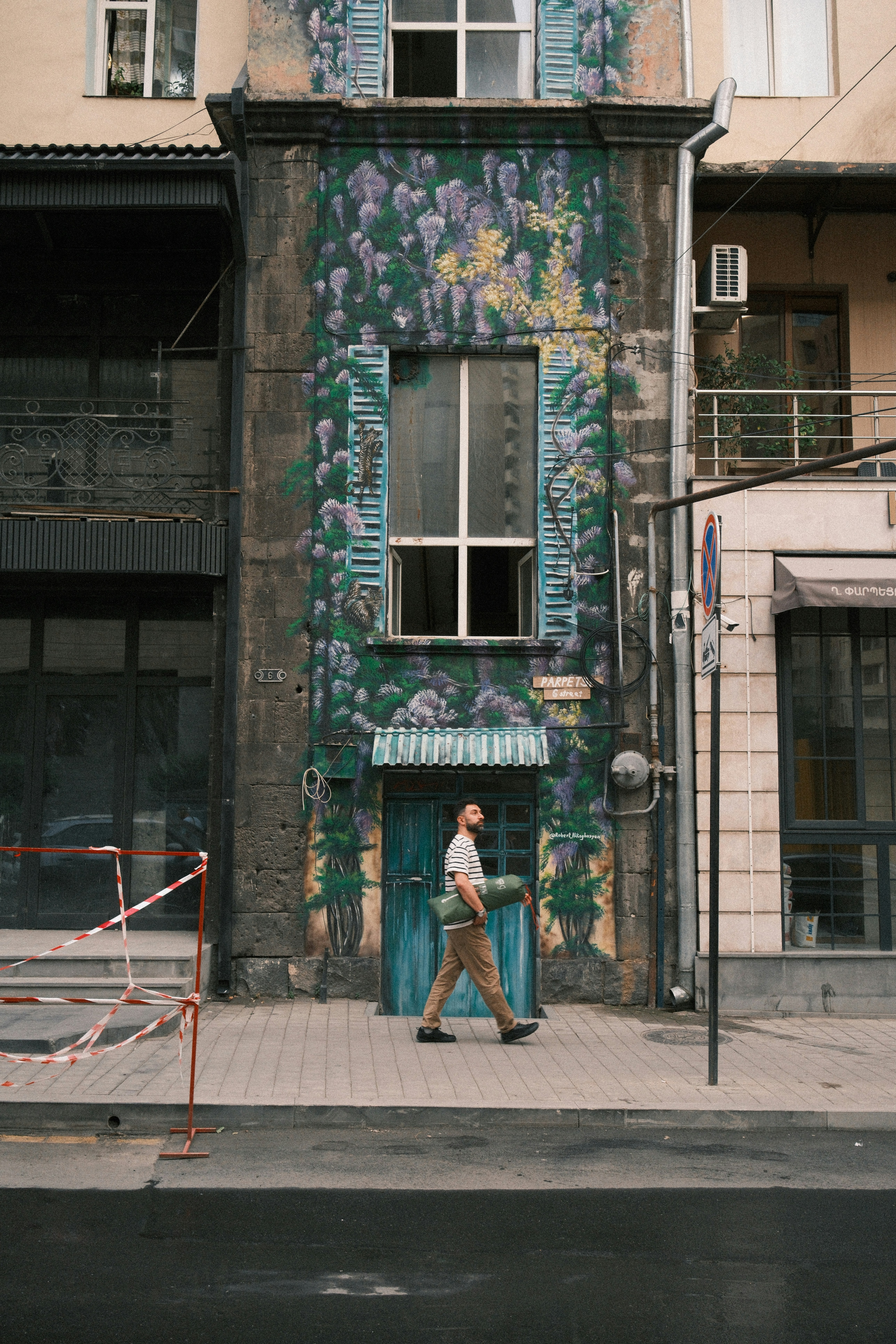 Urban mural doorway: a passerby steps through a painted facade