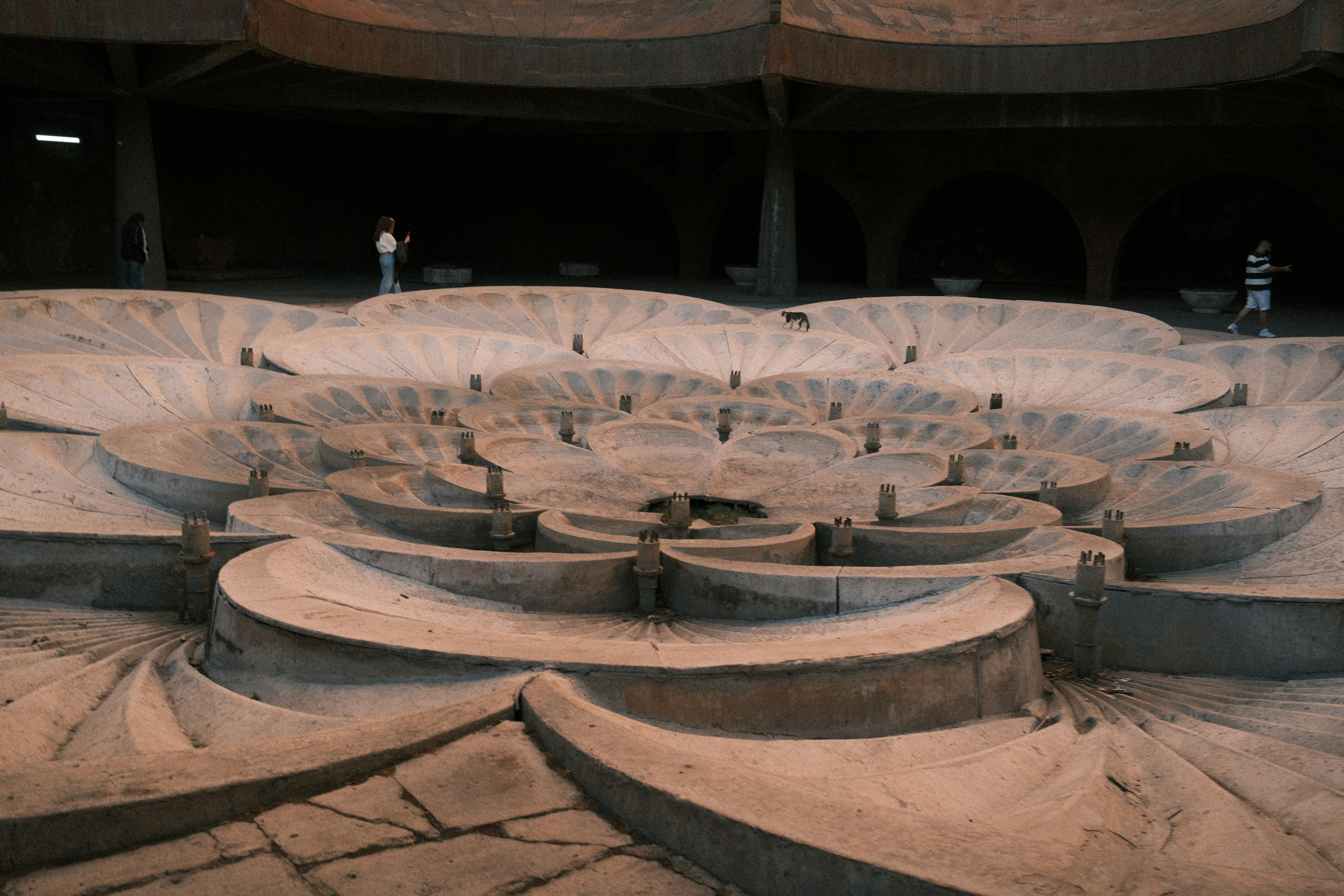 Circular Basins of Stone Lead the Eye Toward the Quiet Keeper at the Edge
