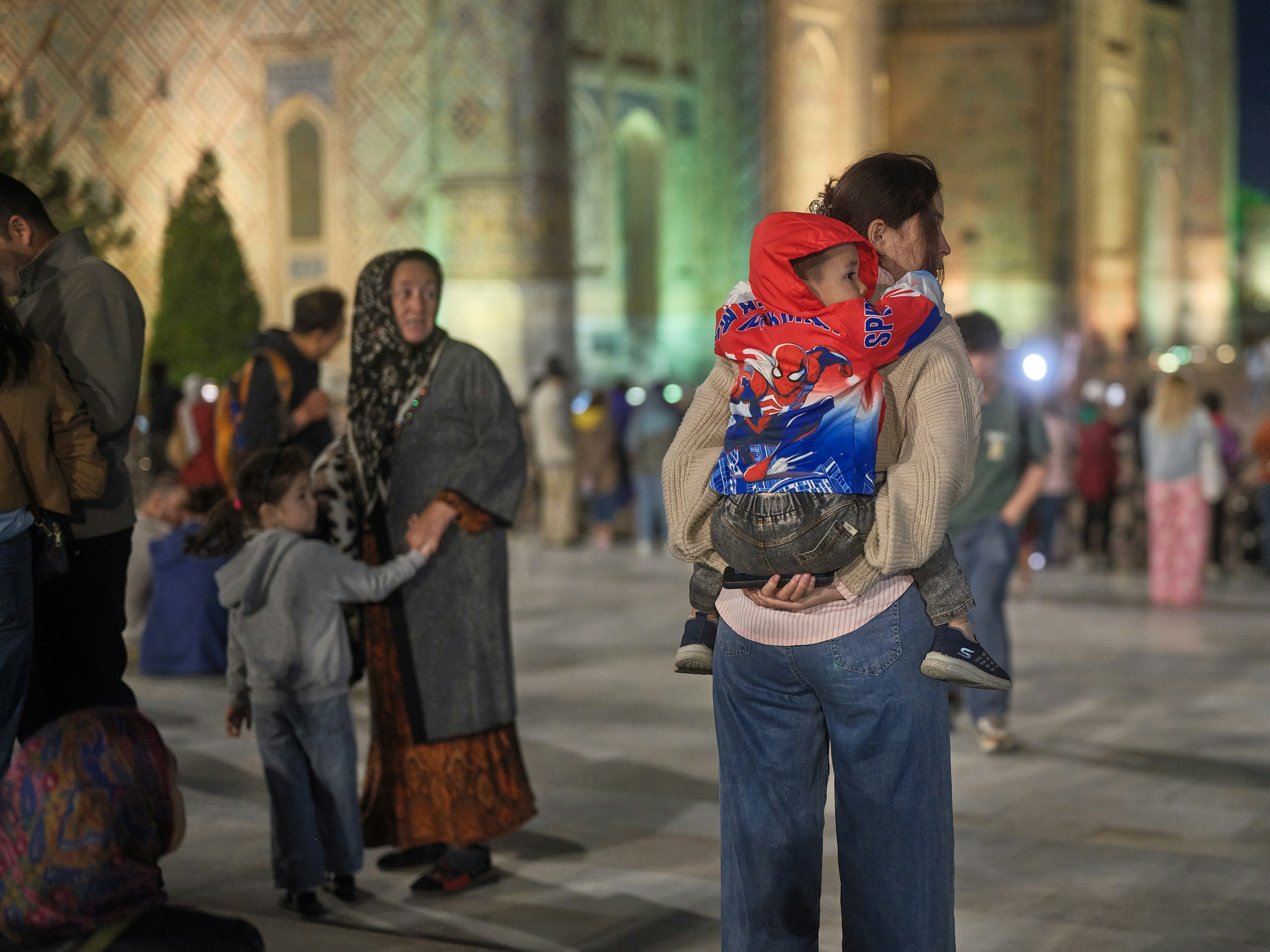 Mother Carrying Child in City Square at Night