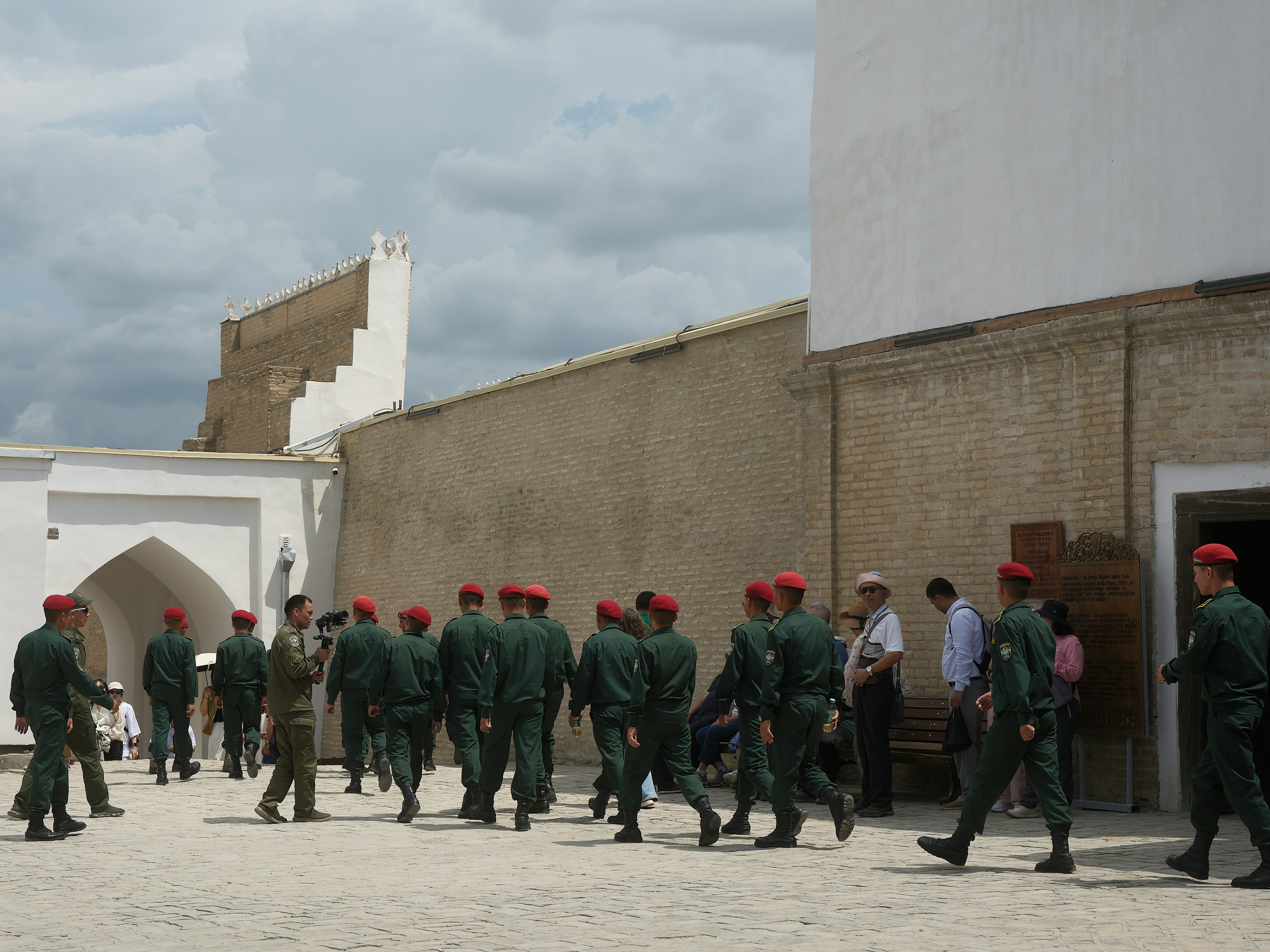 Marching in sync: red-capped cadets toward a sunlit courtyard