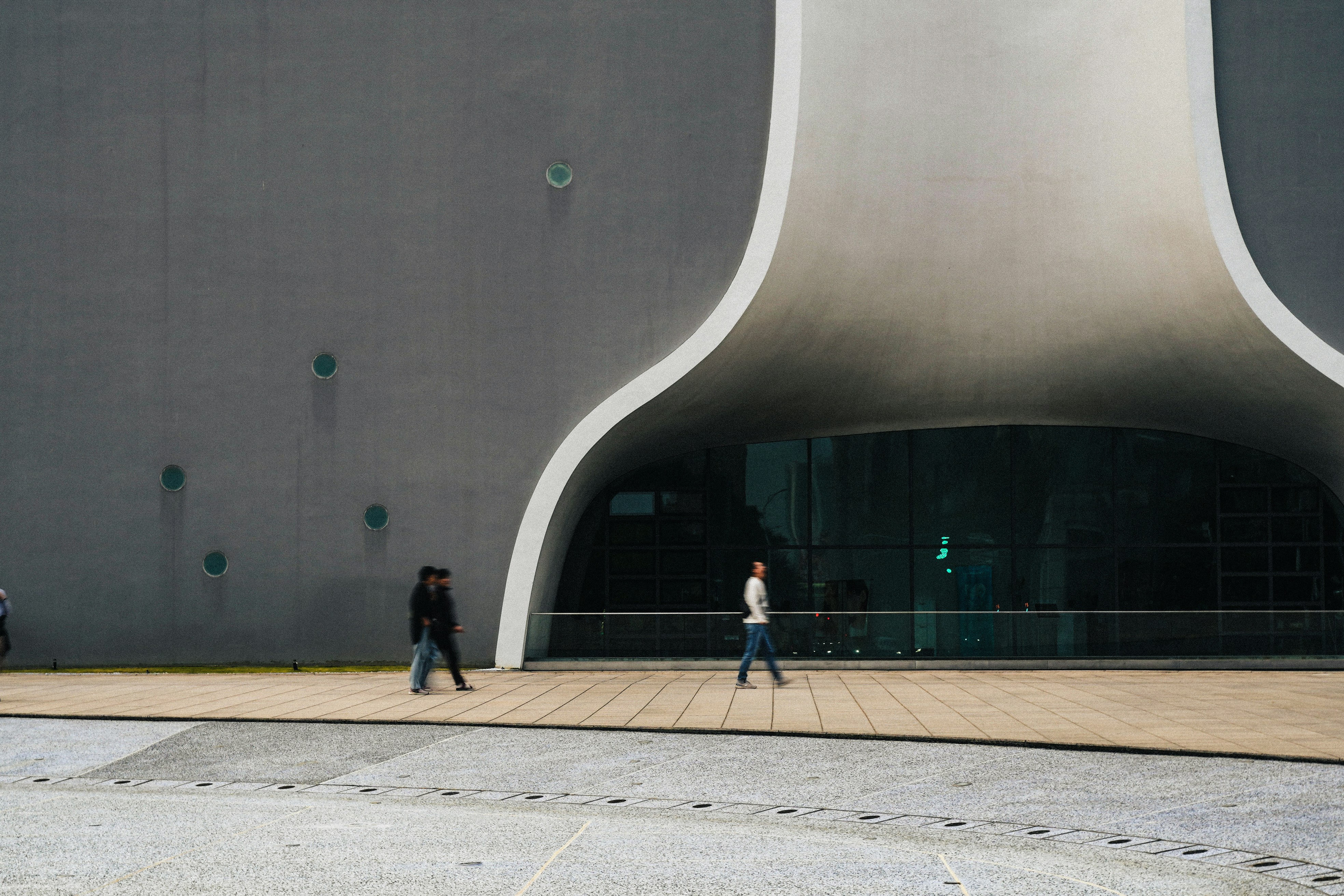 Curved Facade Courtyard: A Minimal Pace Before the Glass