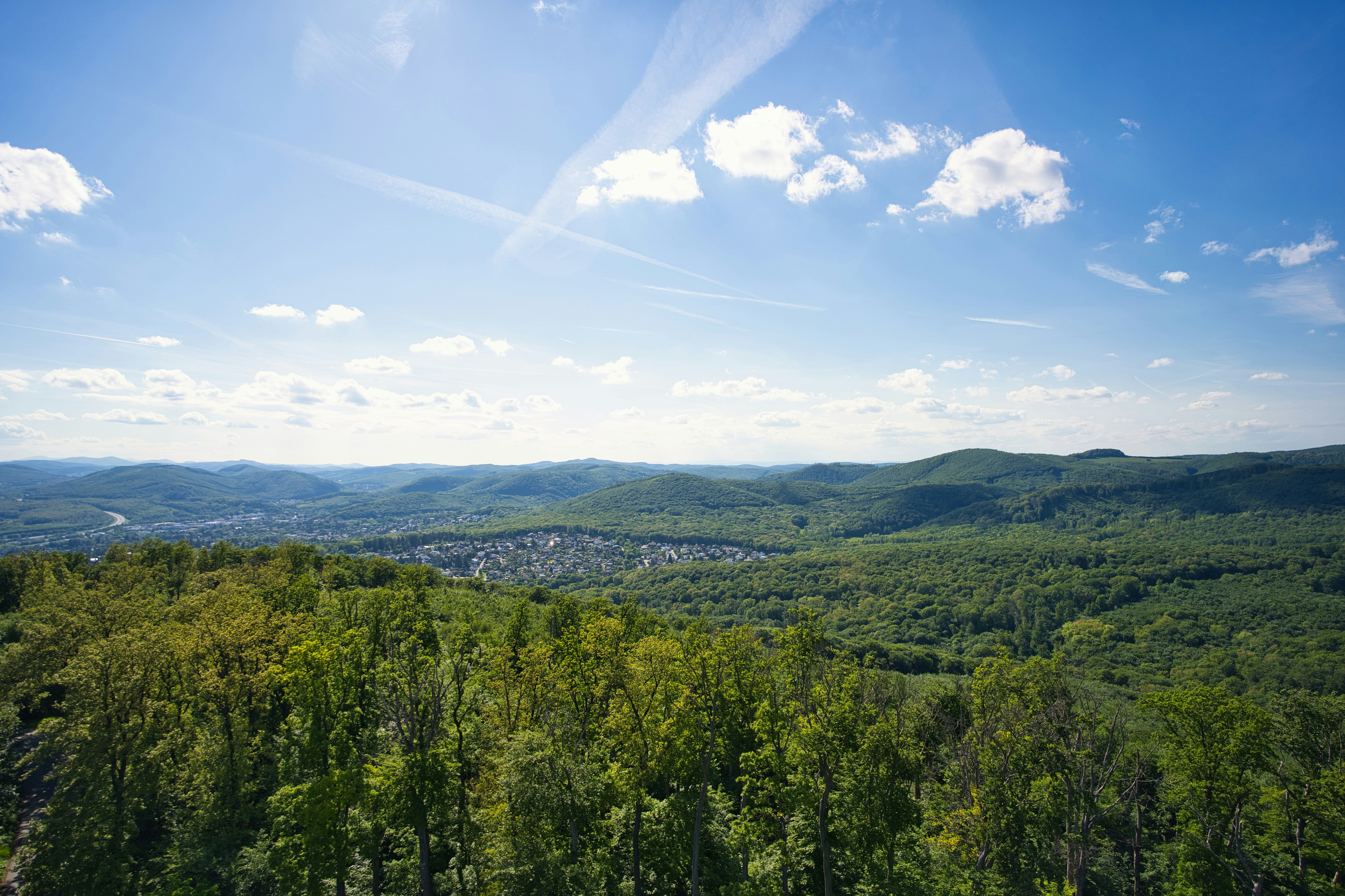 Vast Blue Sky Over Rolling Timber with a Quiet Valley Town