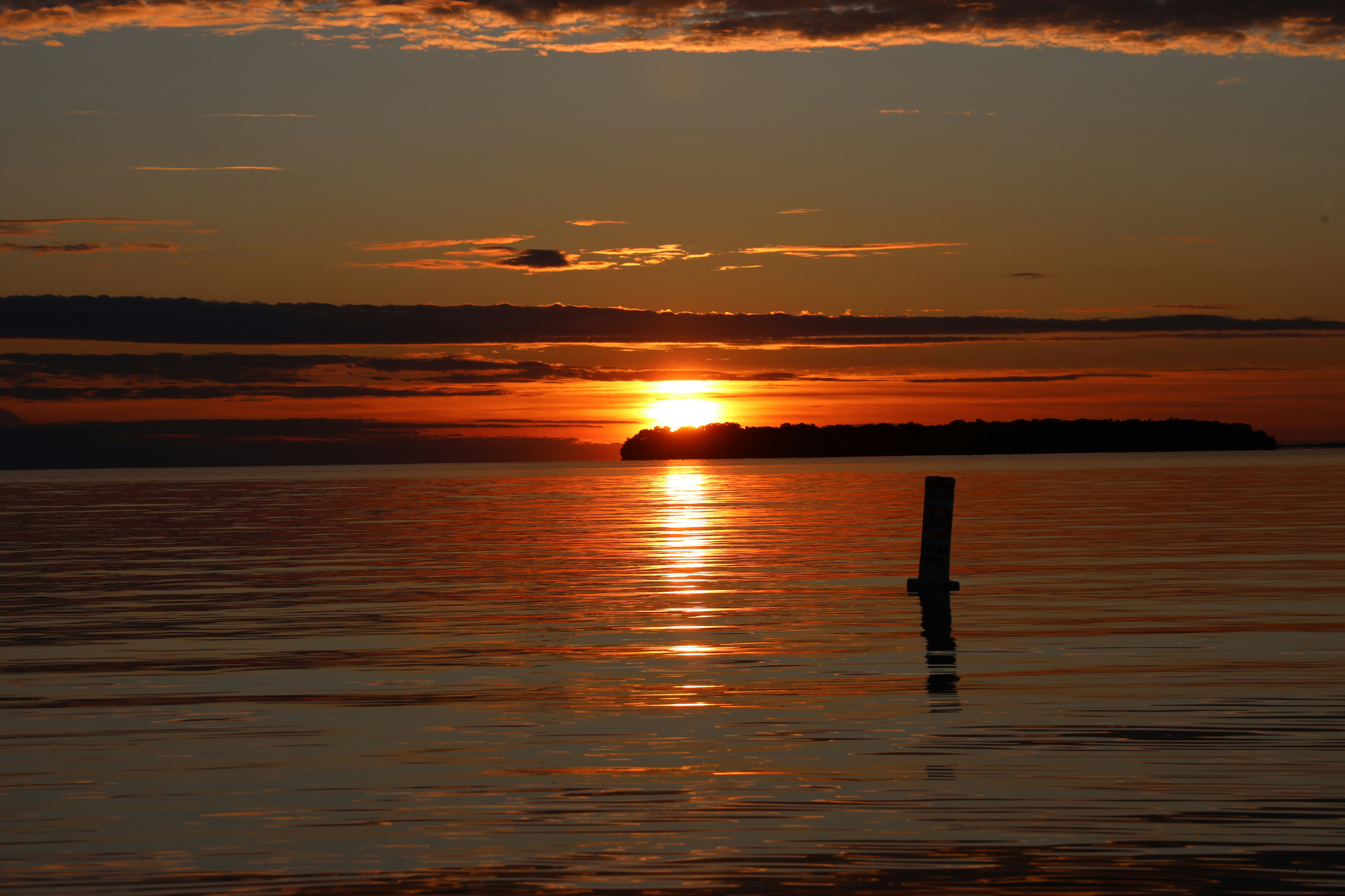 Sunset on a Calm Lake: Silhouette of a Marker Post at Dusk