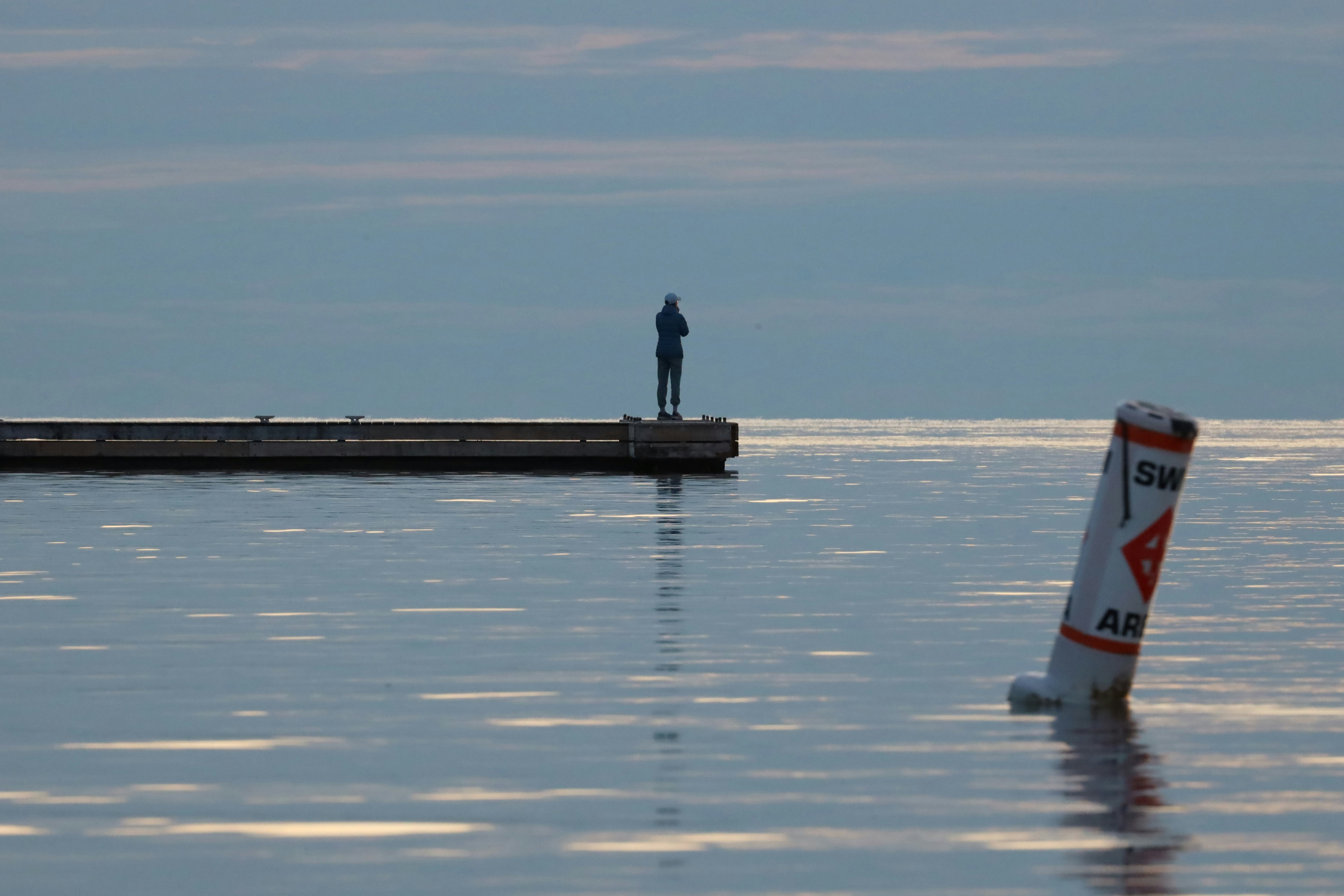  lone figure at the end of a misty jetty over calm water