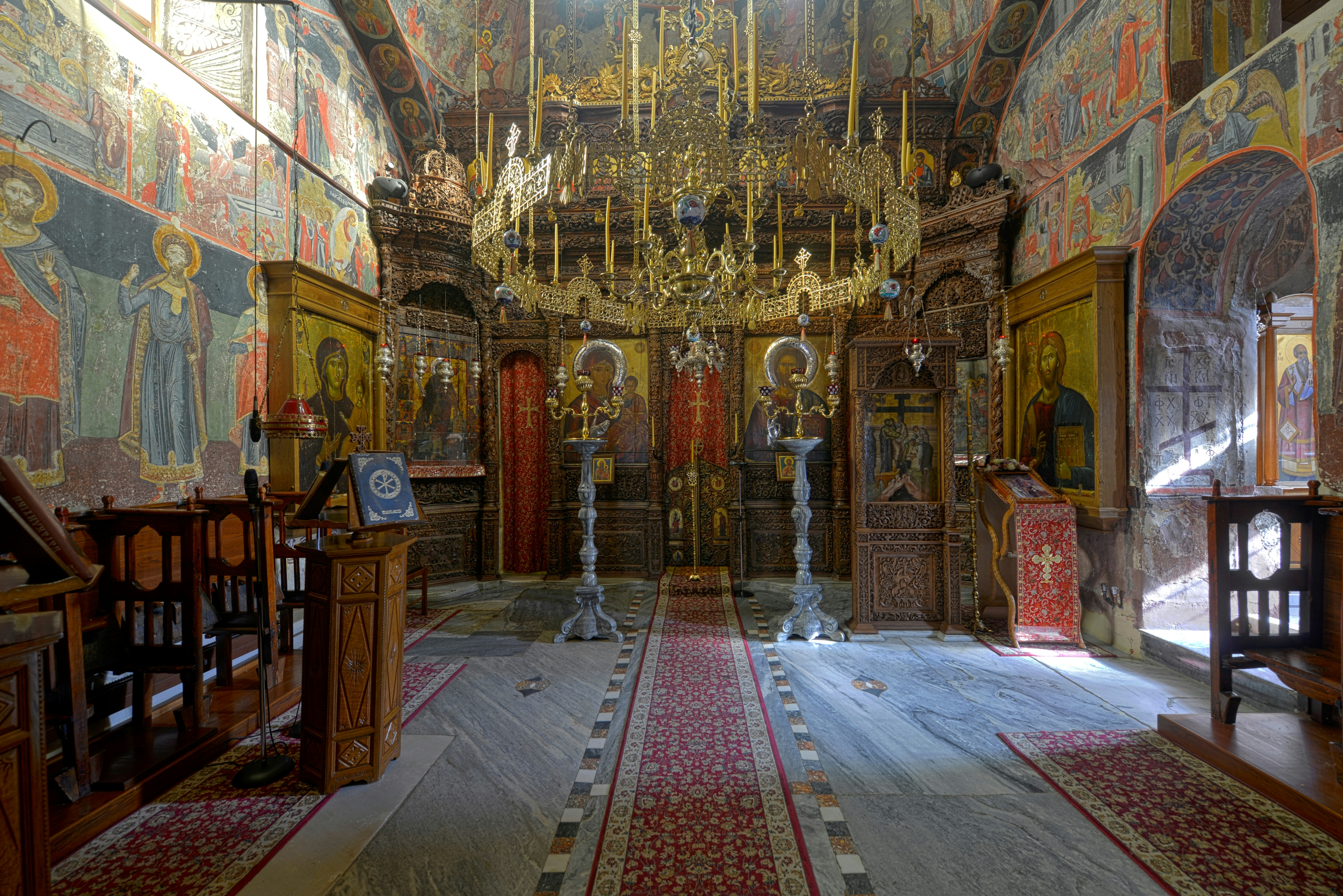 A candlelit Byzantine church interior with gilded chandeliers, icons, and ornate woodwork, inviting quiet contemplation.
