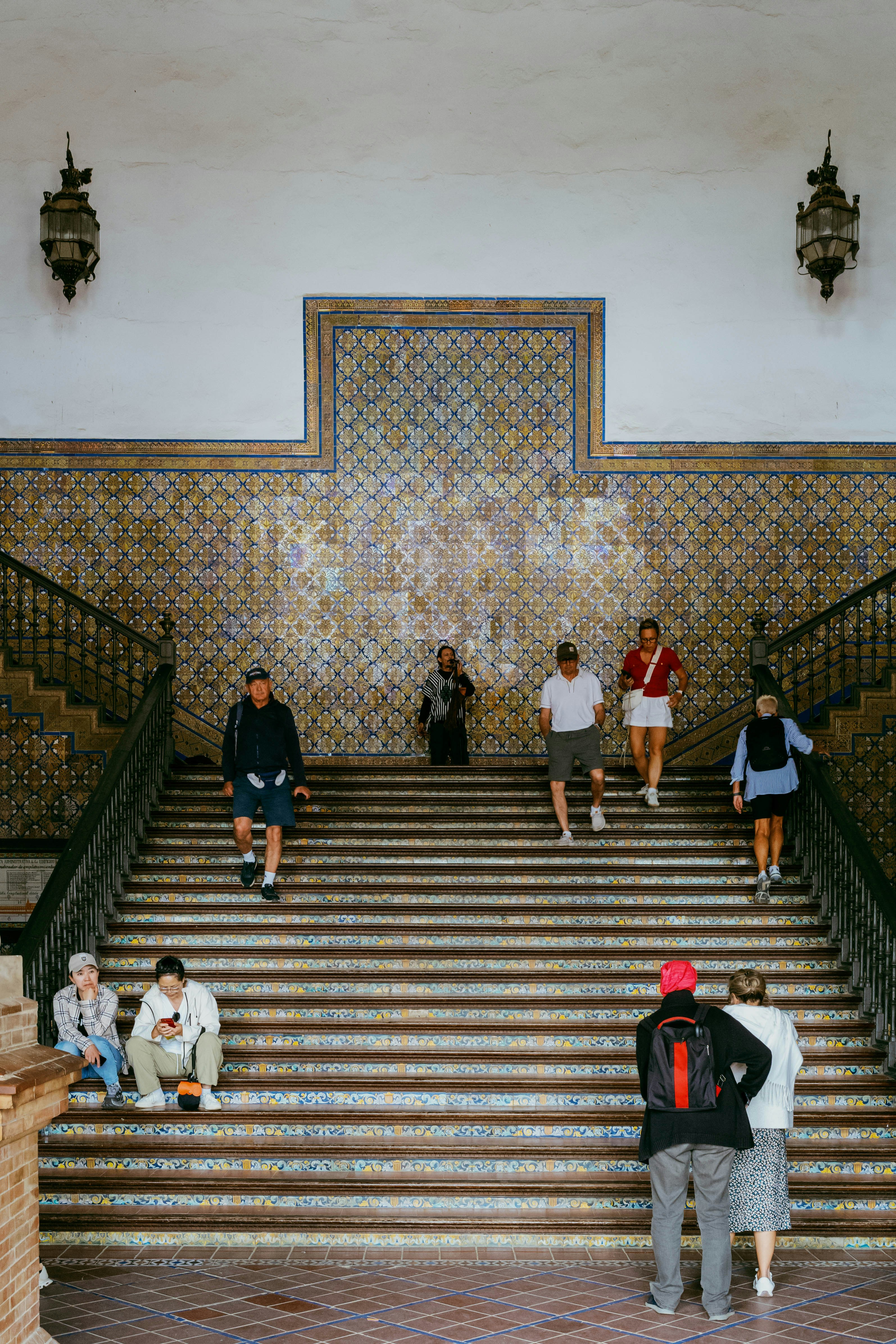 Staircase Confluence: Tourists Descend a Tile-Woven Hall