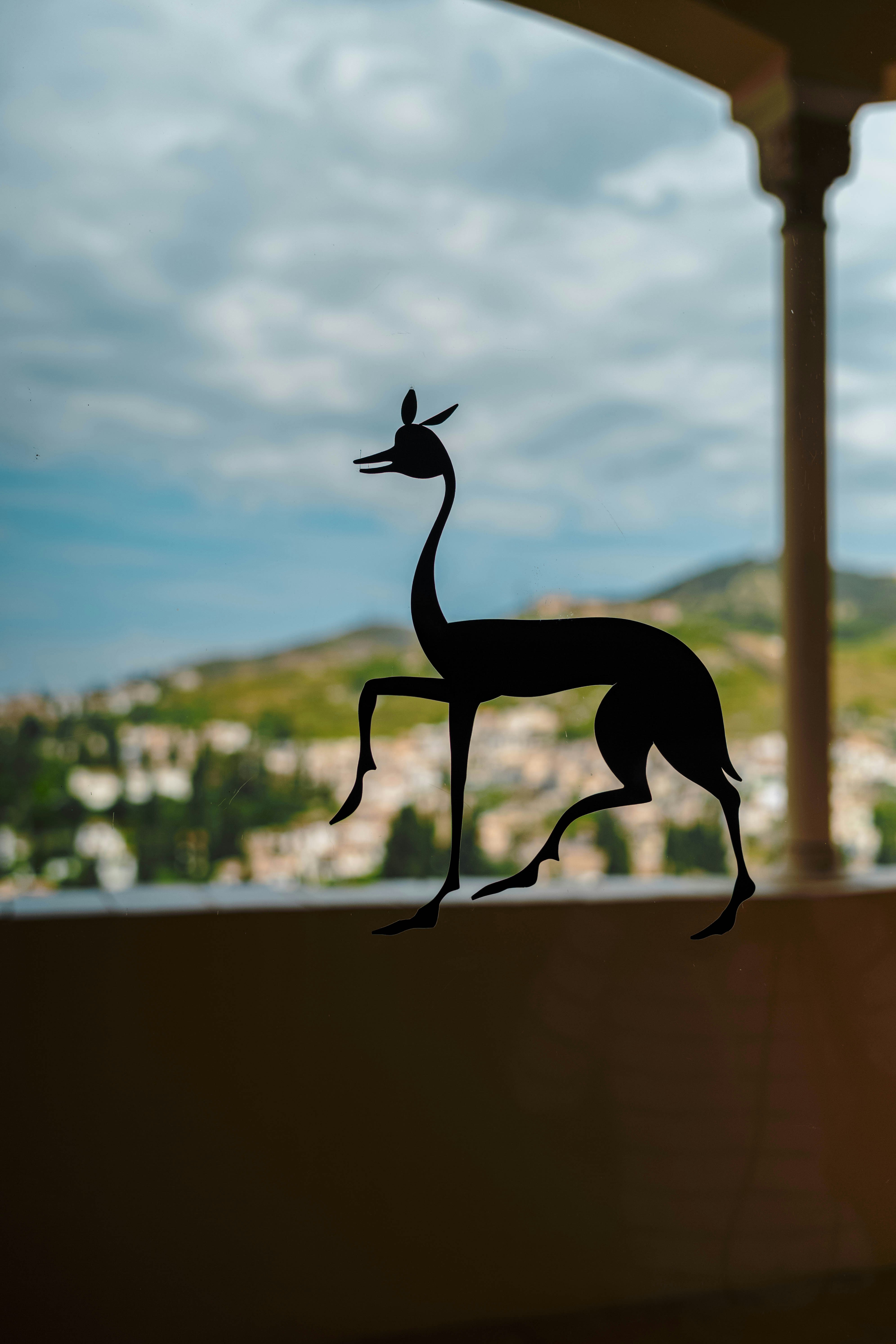 Silhouetted Gazelle Emblem on a Sunlit Terrace Overlooking a Coastal Landscape