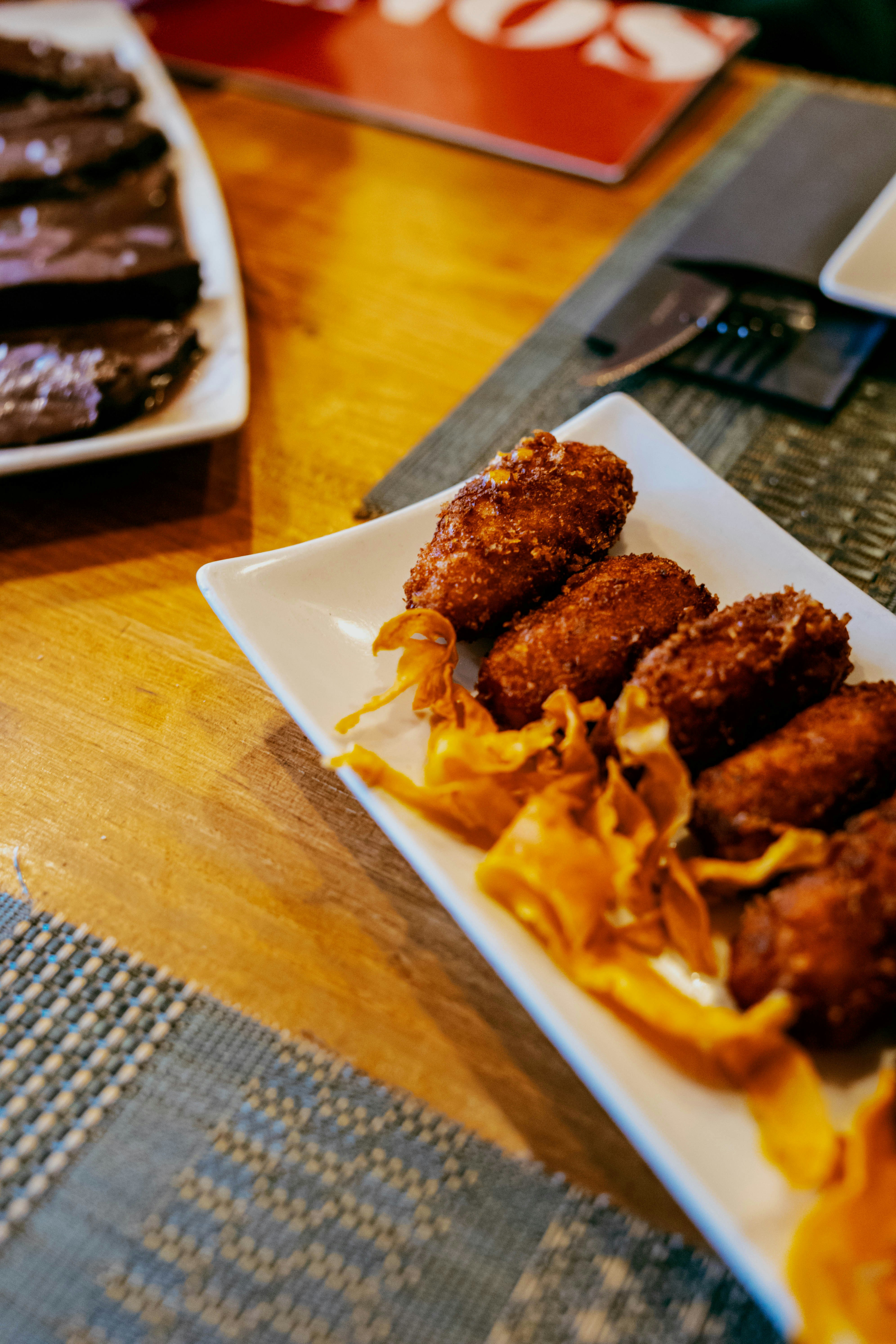 Crisped bites on a wooden table: a plate of croquettes with crispy onions