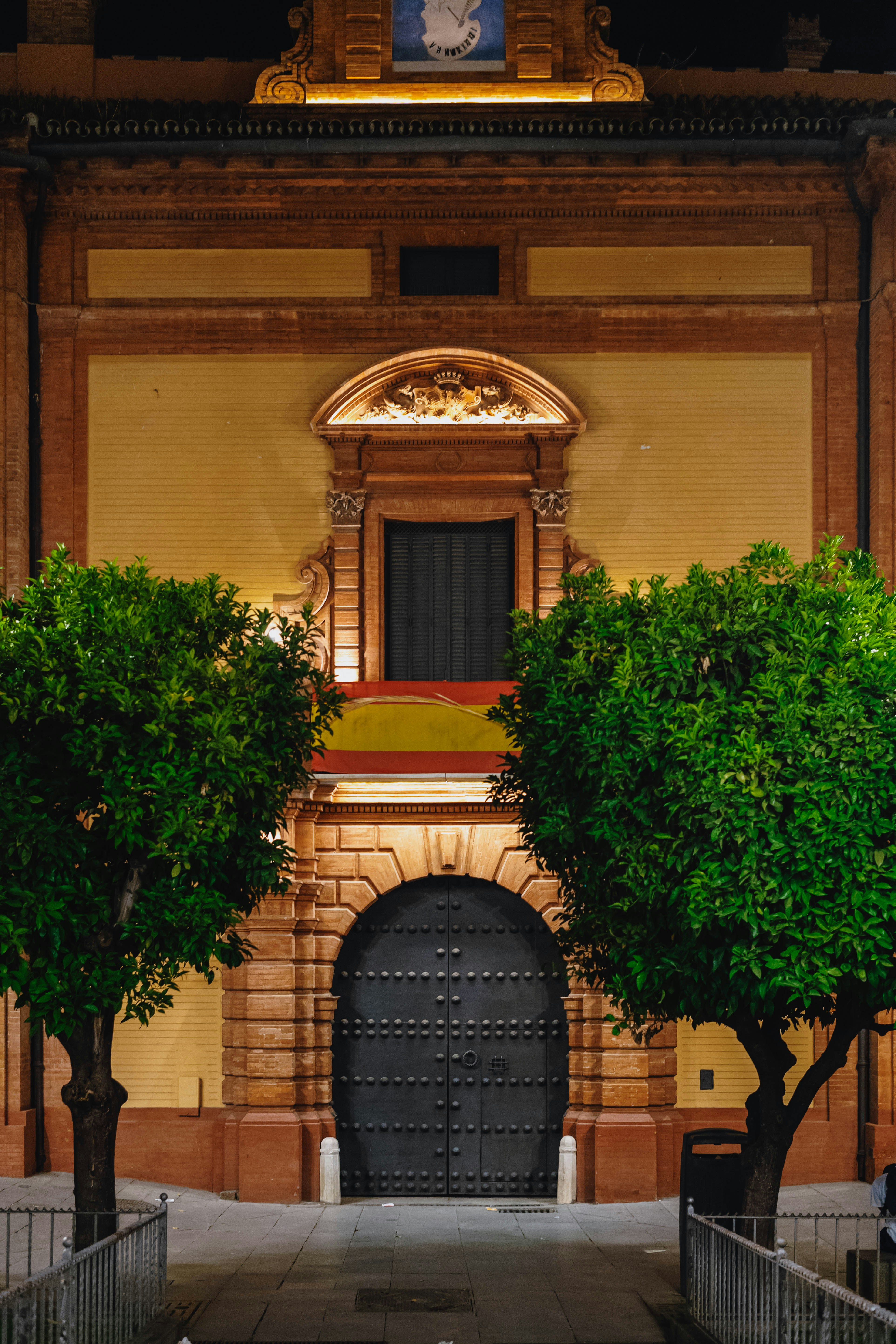 Neoclassical doorway framed by citrus green Cararra trees at night