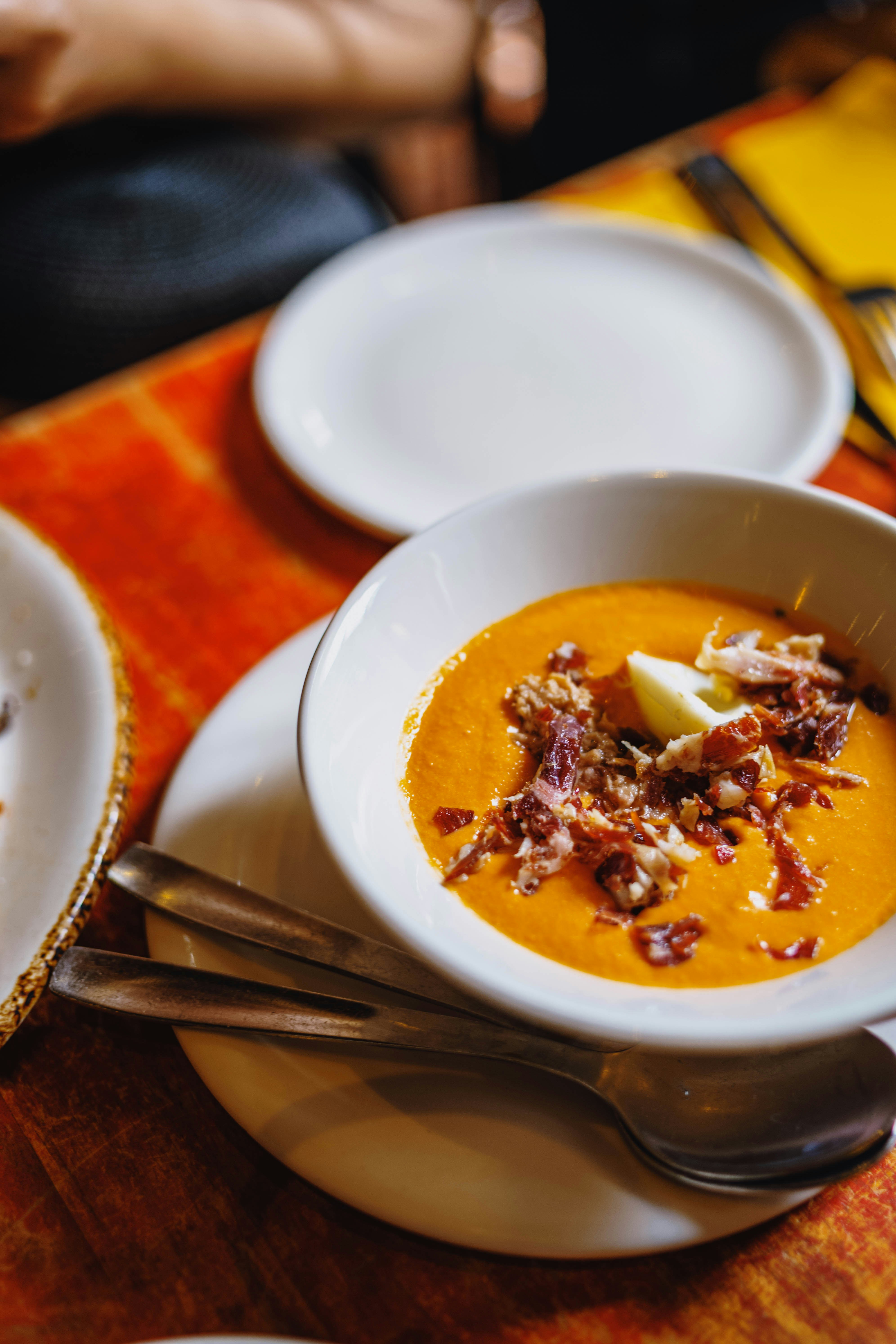 Creamy orange soup crowned with bacon and lemon zest