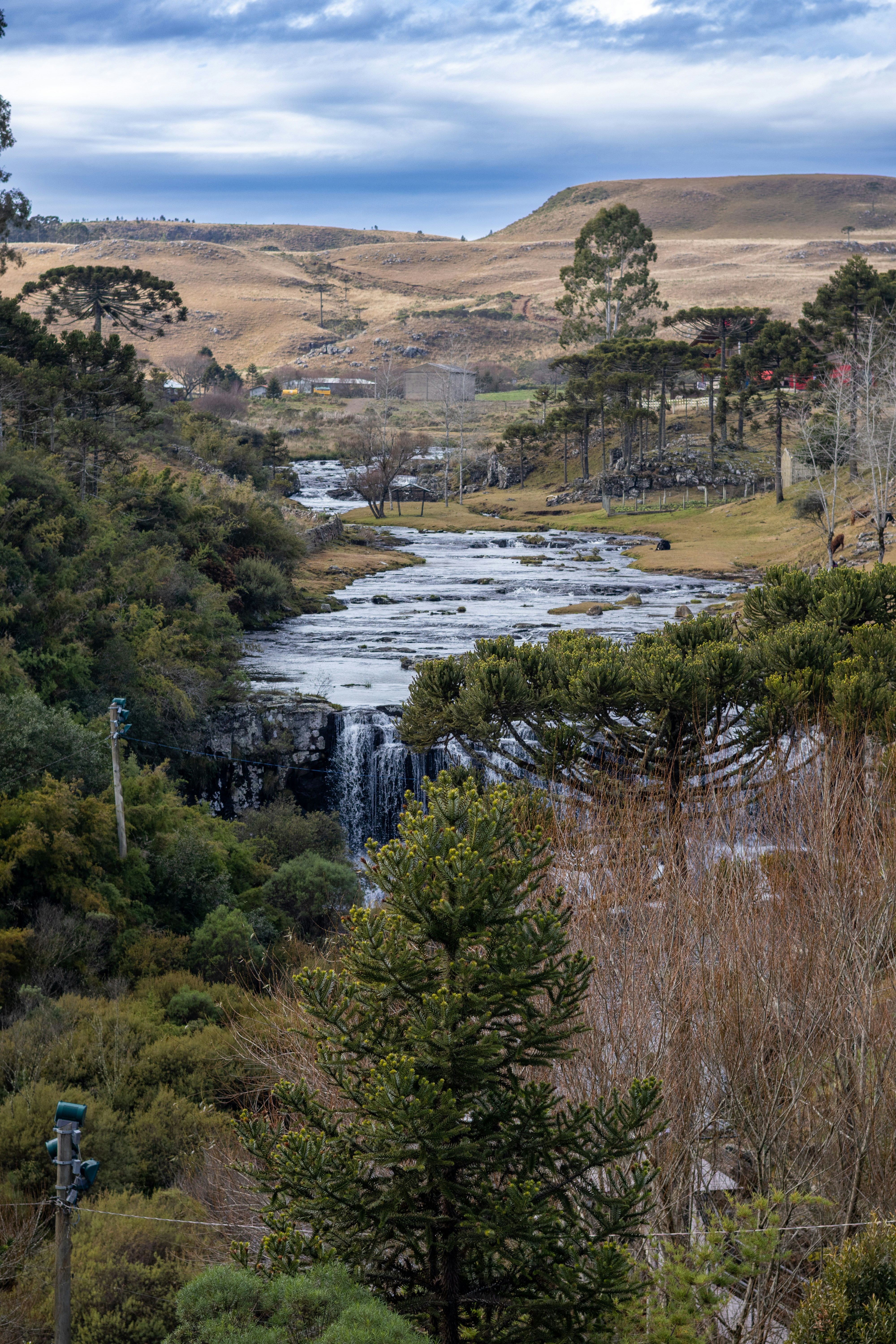 River cascade through rolling hills under a pale sky