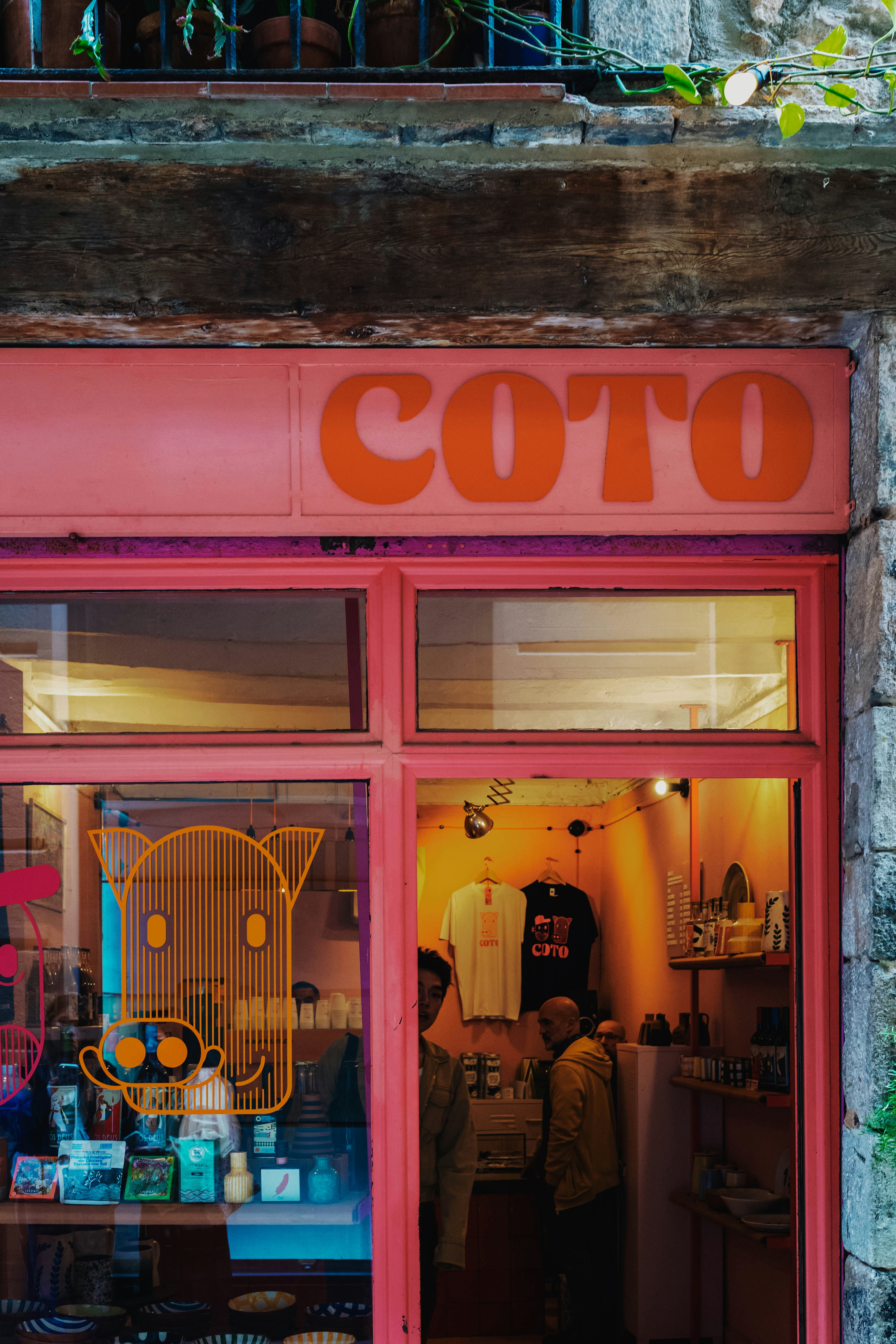Pink storefront glow: COTO shop with warm interior and neon outline