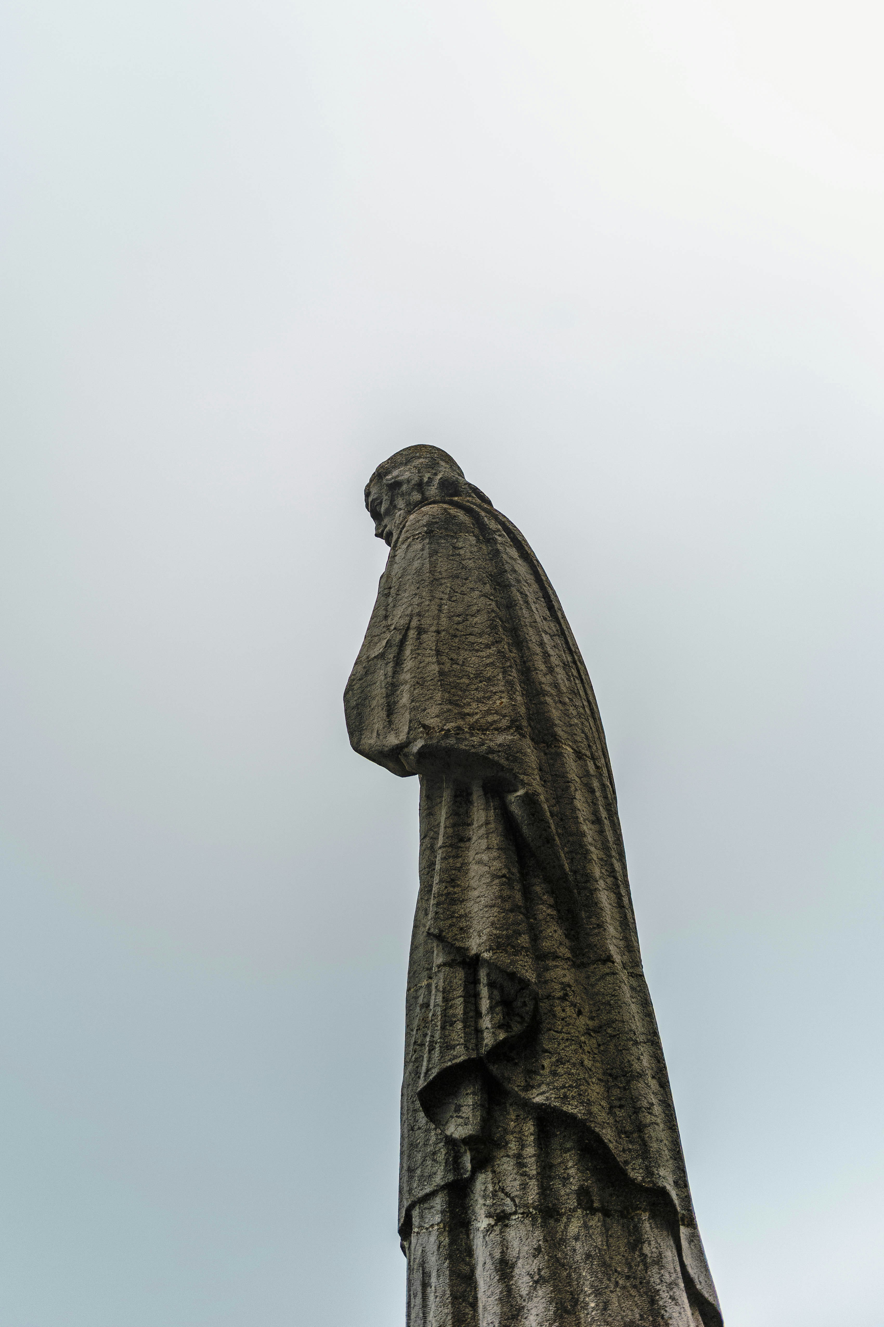 Silent Sentinel: A solitary statue rises against a pale sky
