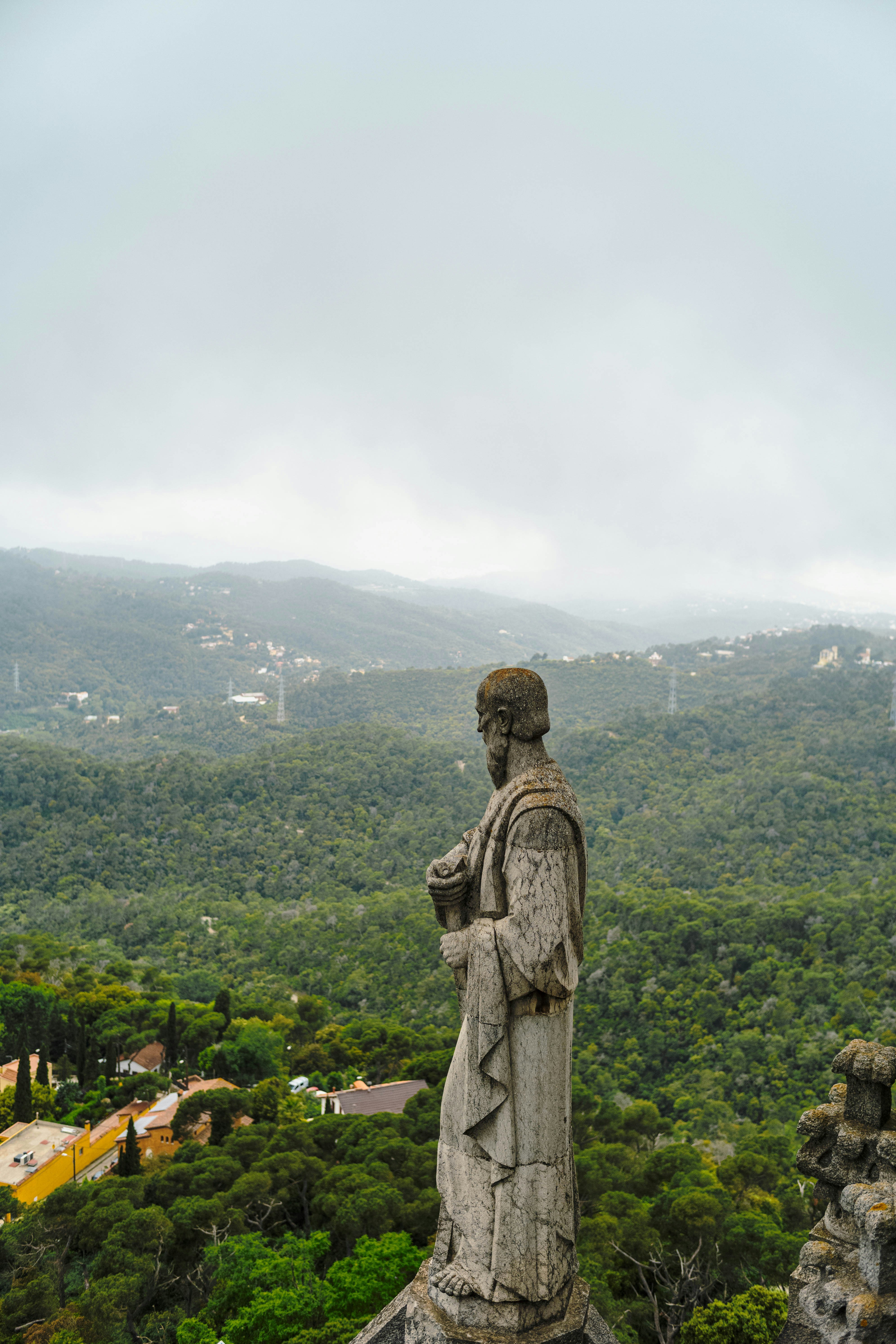 Sentinel in the Clouds: A Stone Statue Overlooking Green Valleys