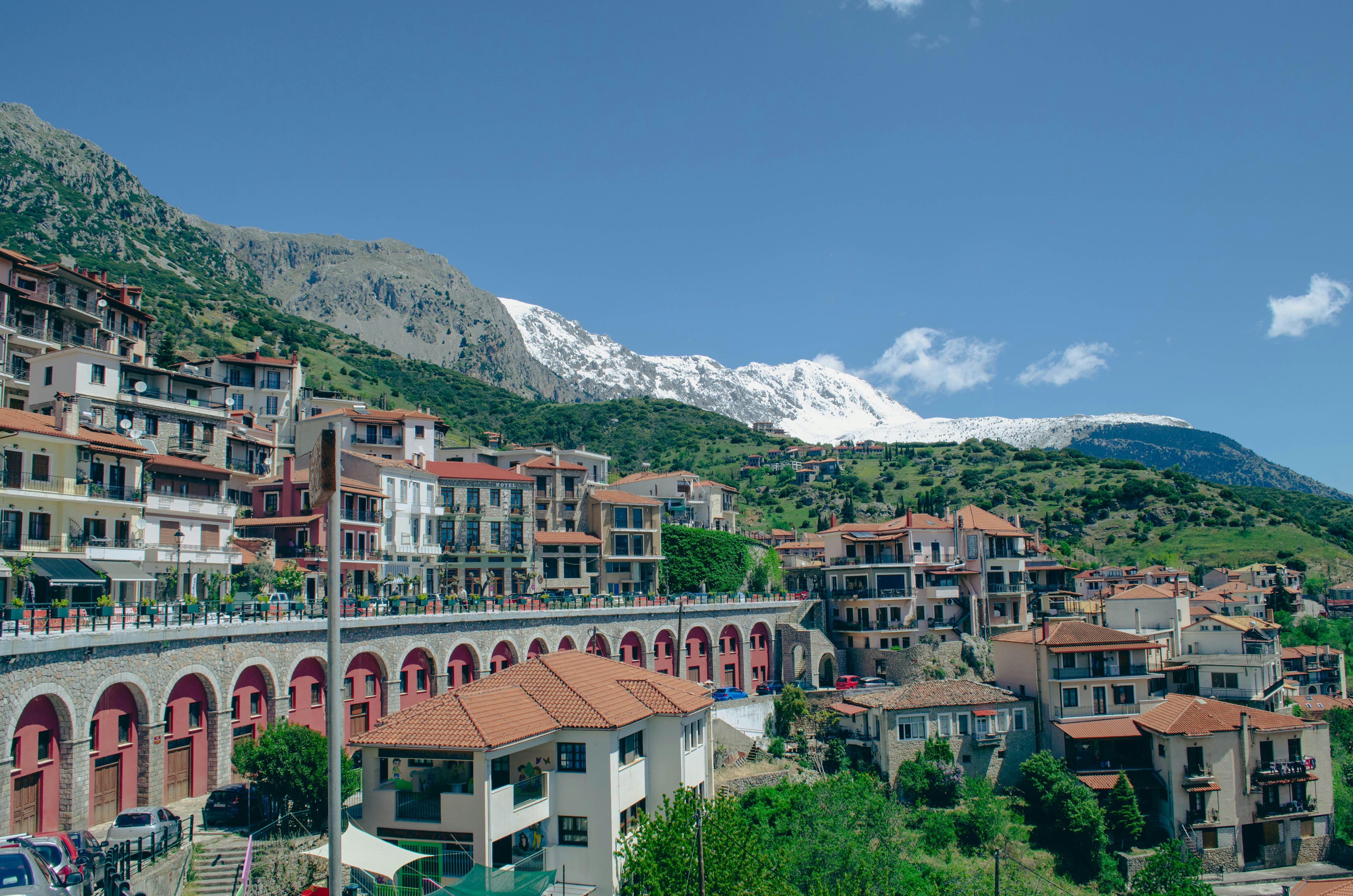  hillside village arches and pastel buildings beneath snow‑capped peaks