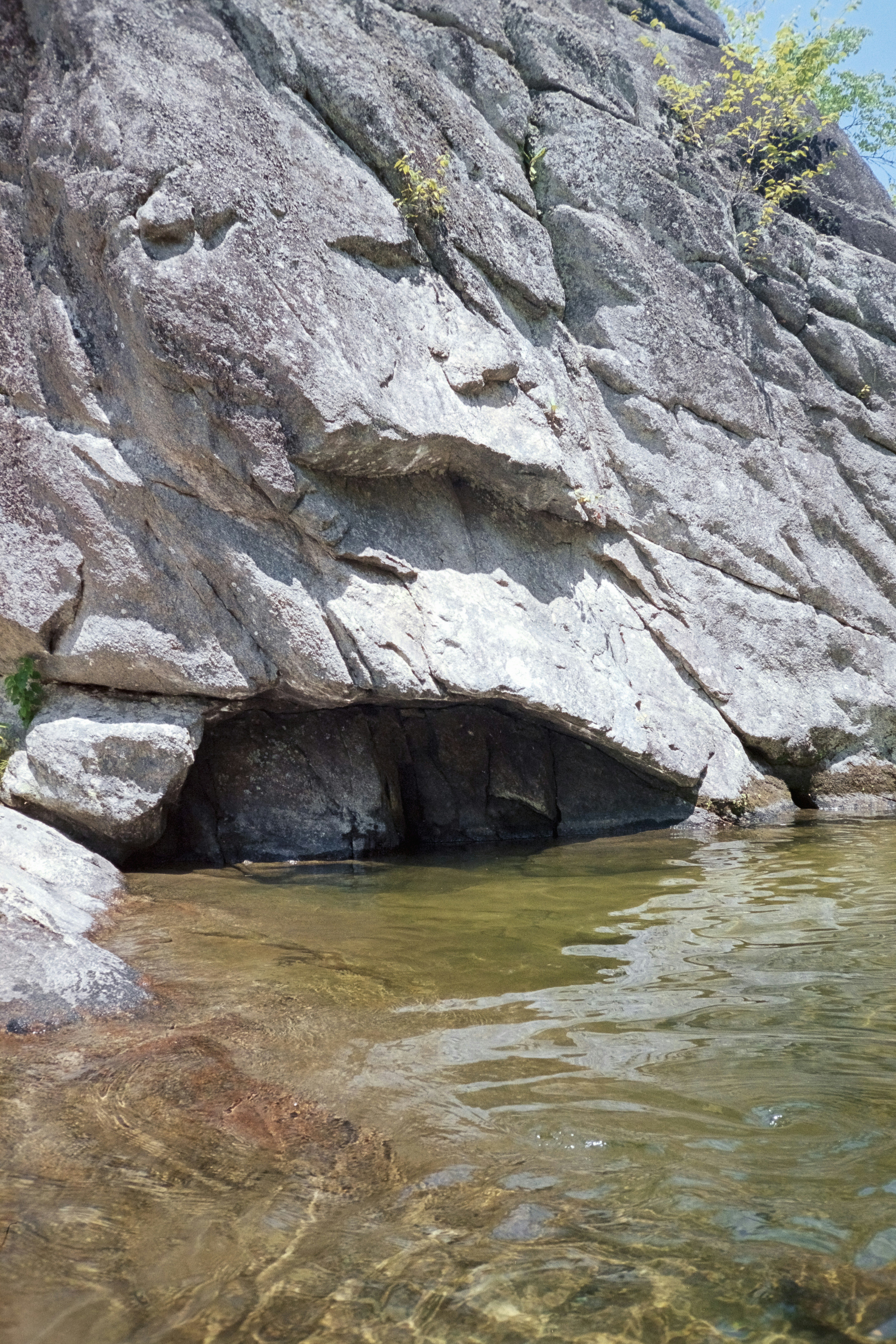 Stone Cliff Overhang by Calm Rippling Water