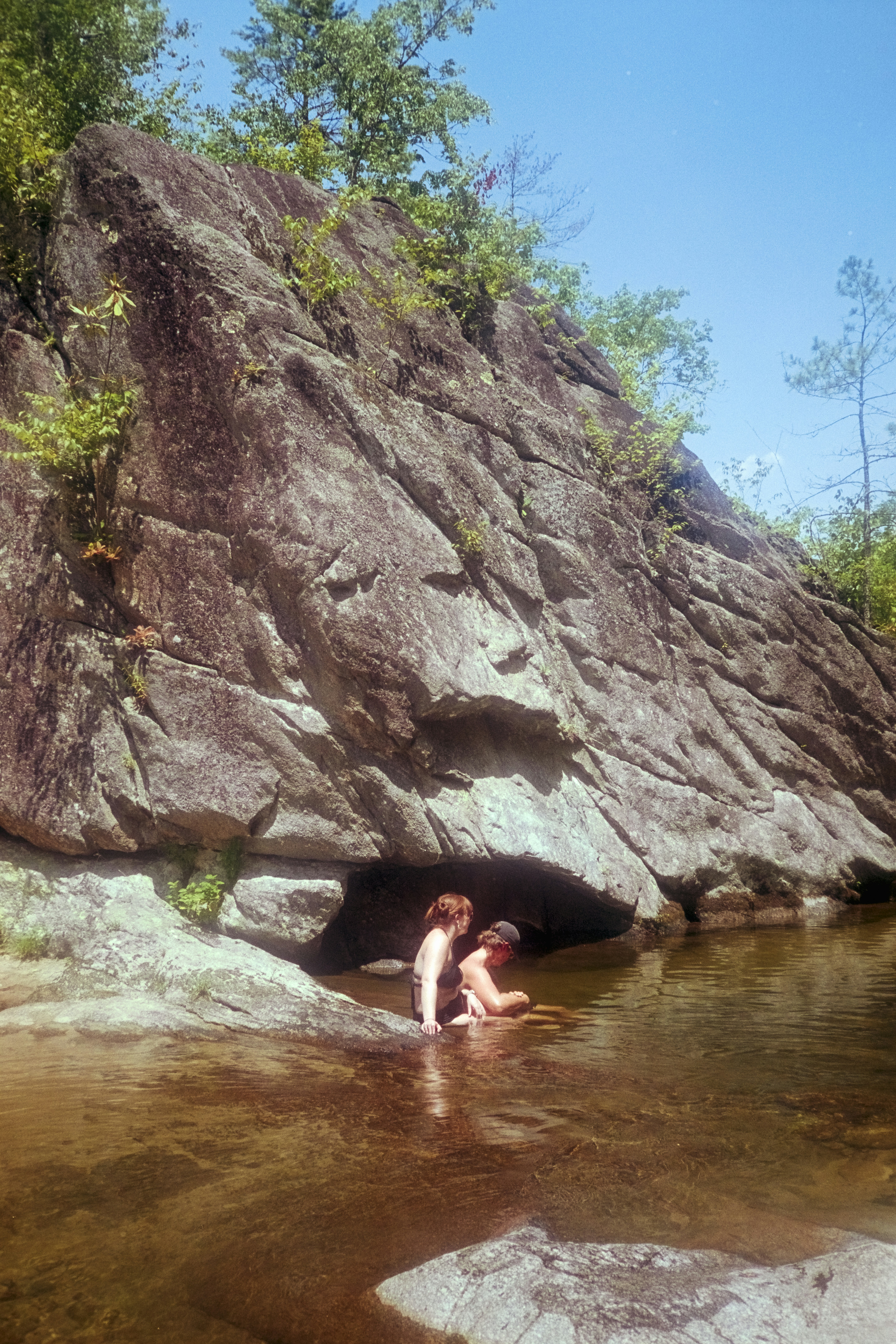 Children Wading by a Caved Rock Overlook at the River