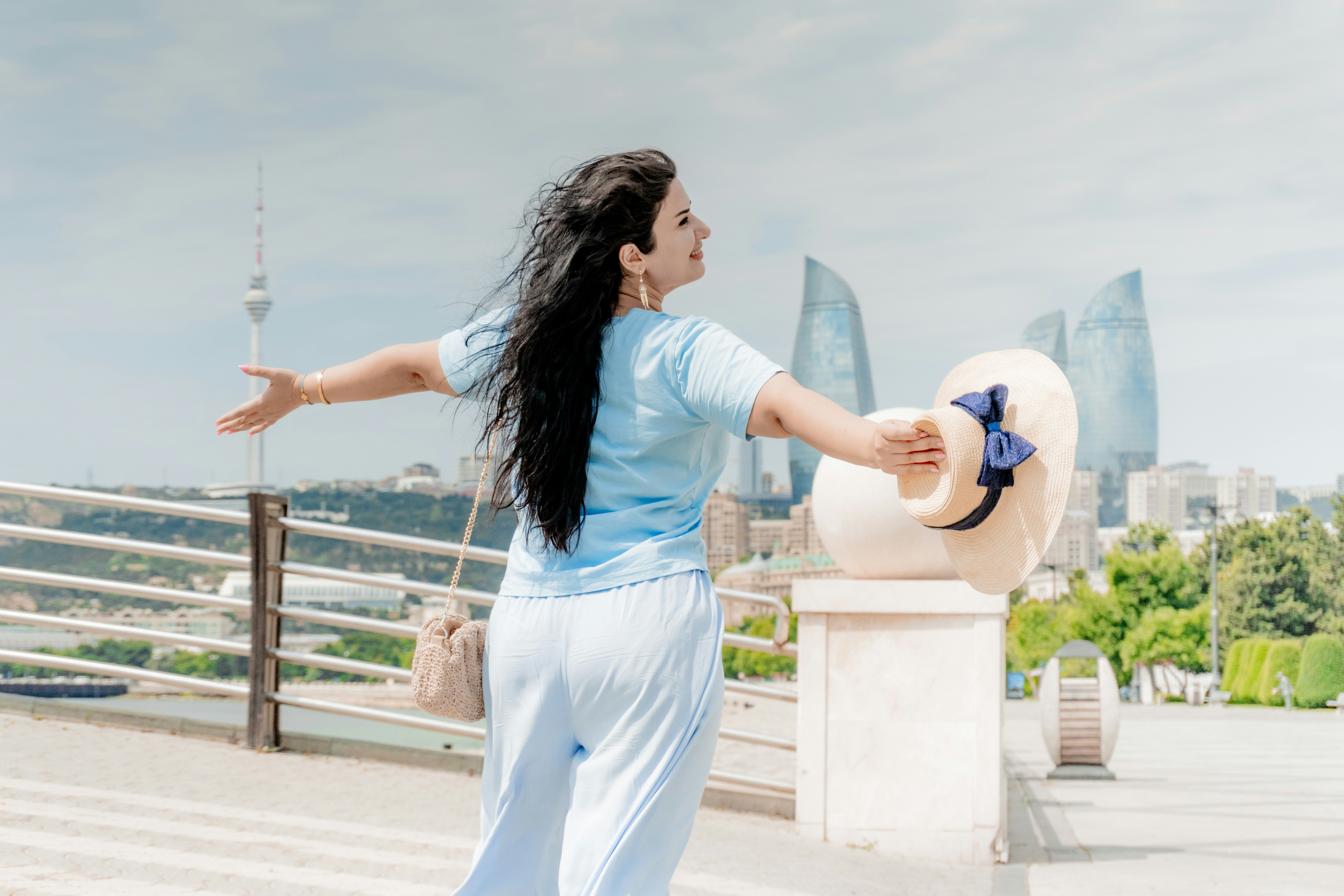 Open Horizon: A Woman Spreads Her Arms in a Sunny Coastal Walk