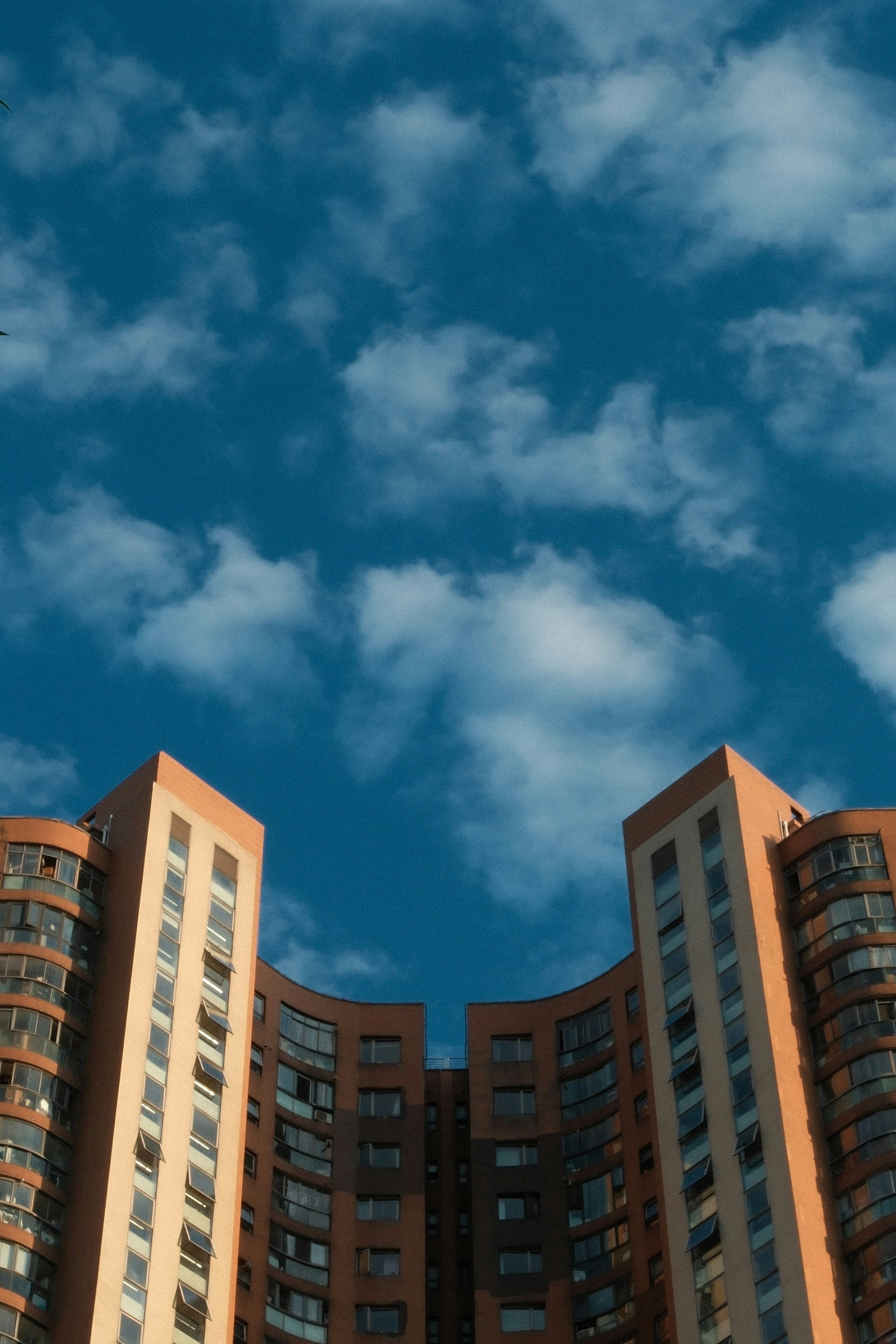 Sunlit brick arc: skyward view between curved towers