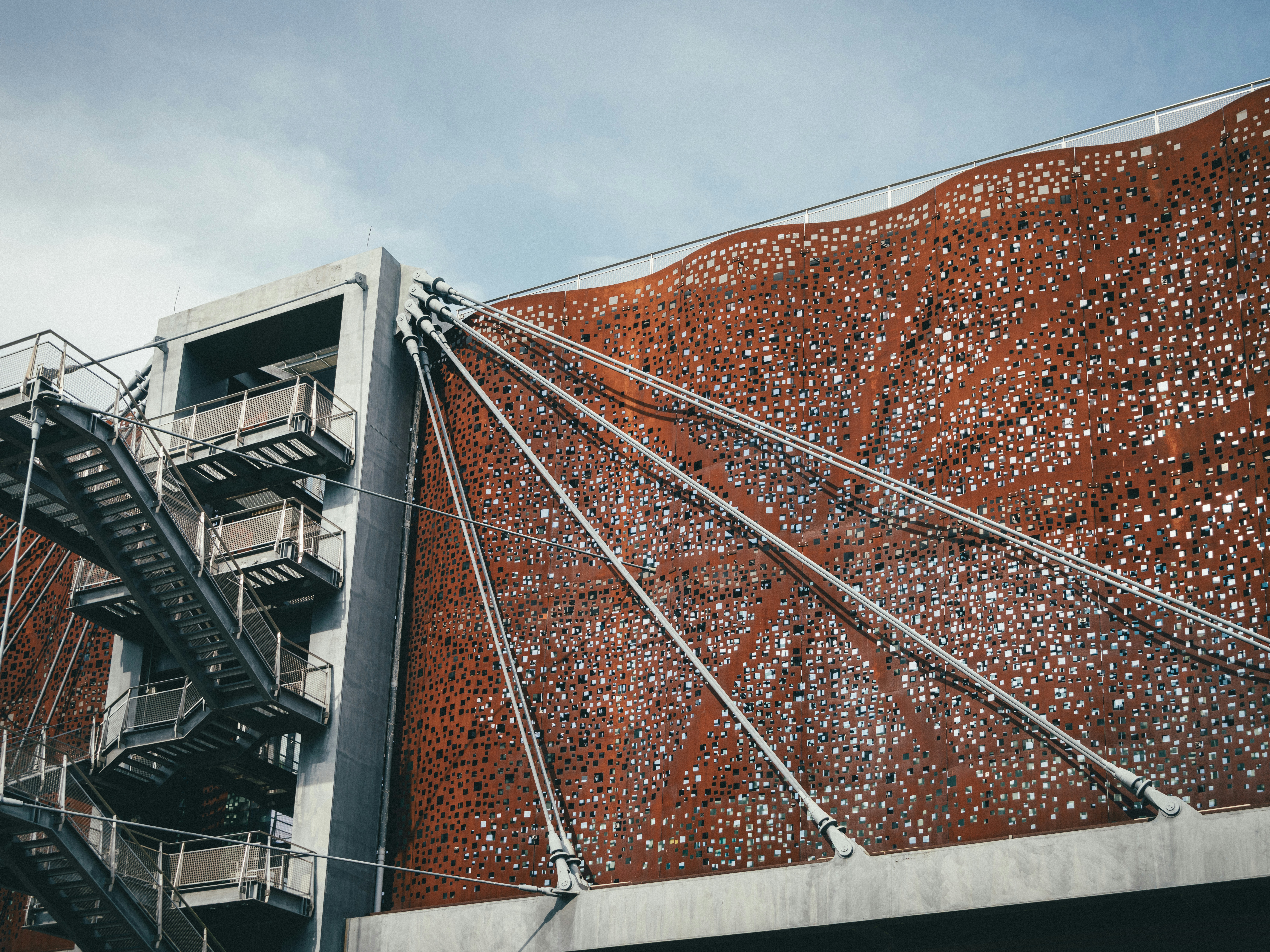 Cabled Facade: Steel Struts Meet Rusted Perforations