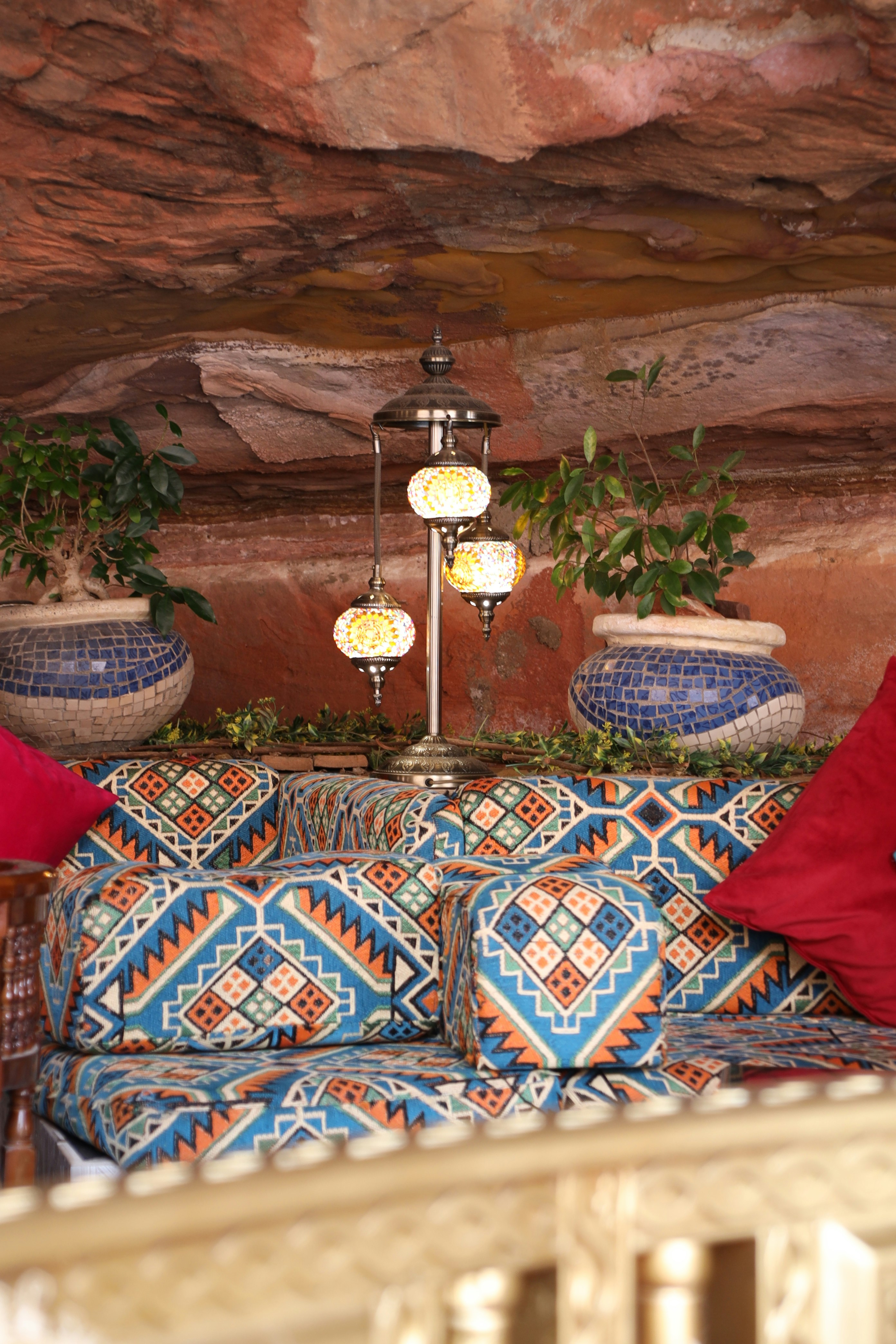 Lanterns on a mosaic couch beneath a sandstone alcove