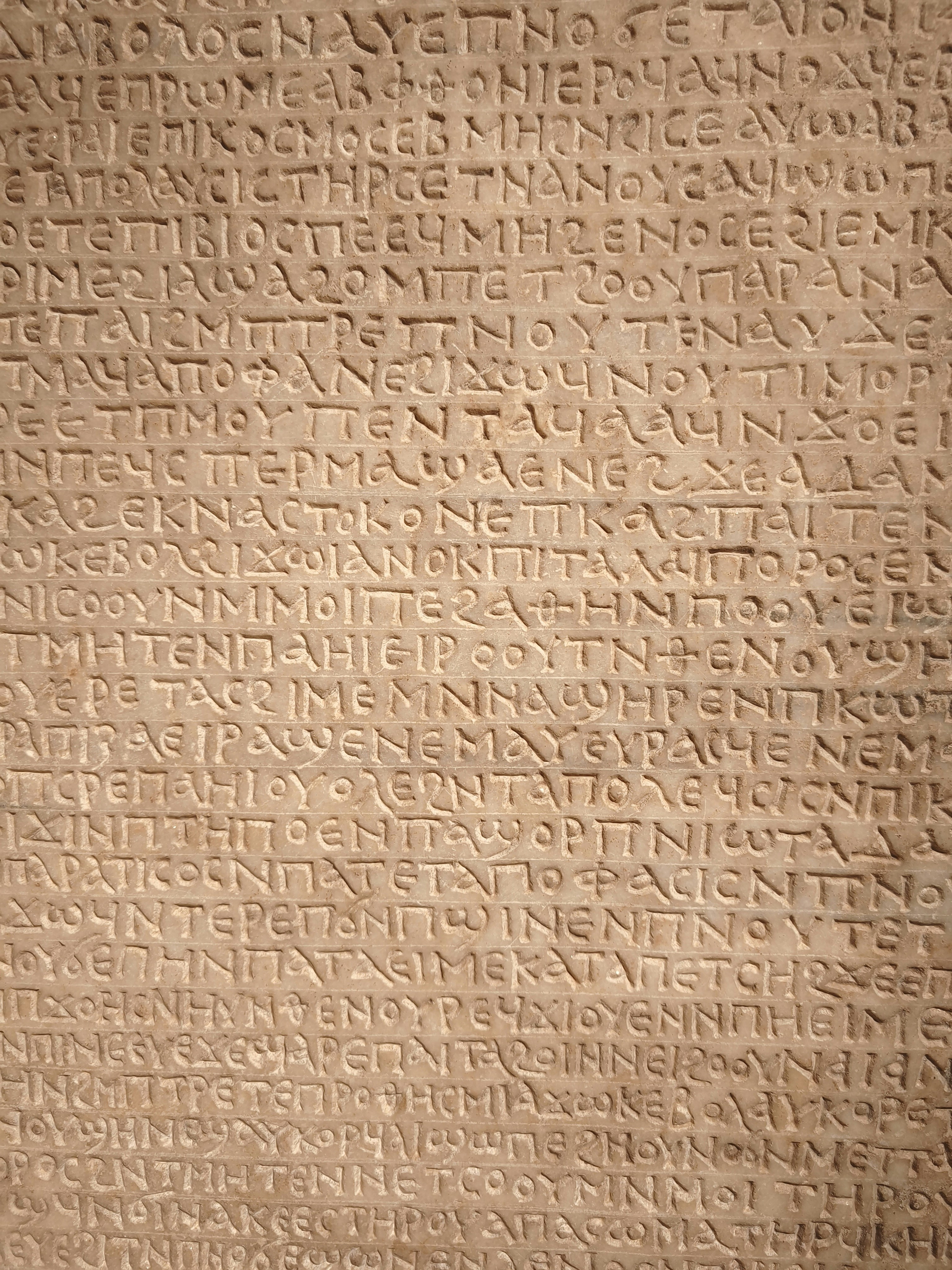 Stone slab covered with evenly carved ancient glyphs forming a dense, uniform inscription across the surface.
