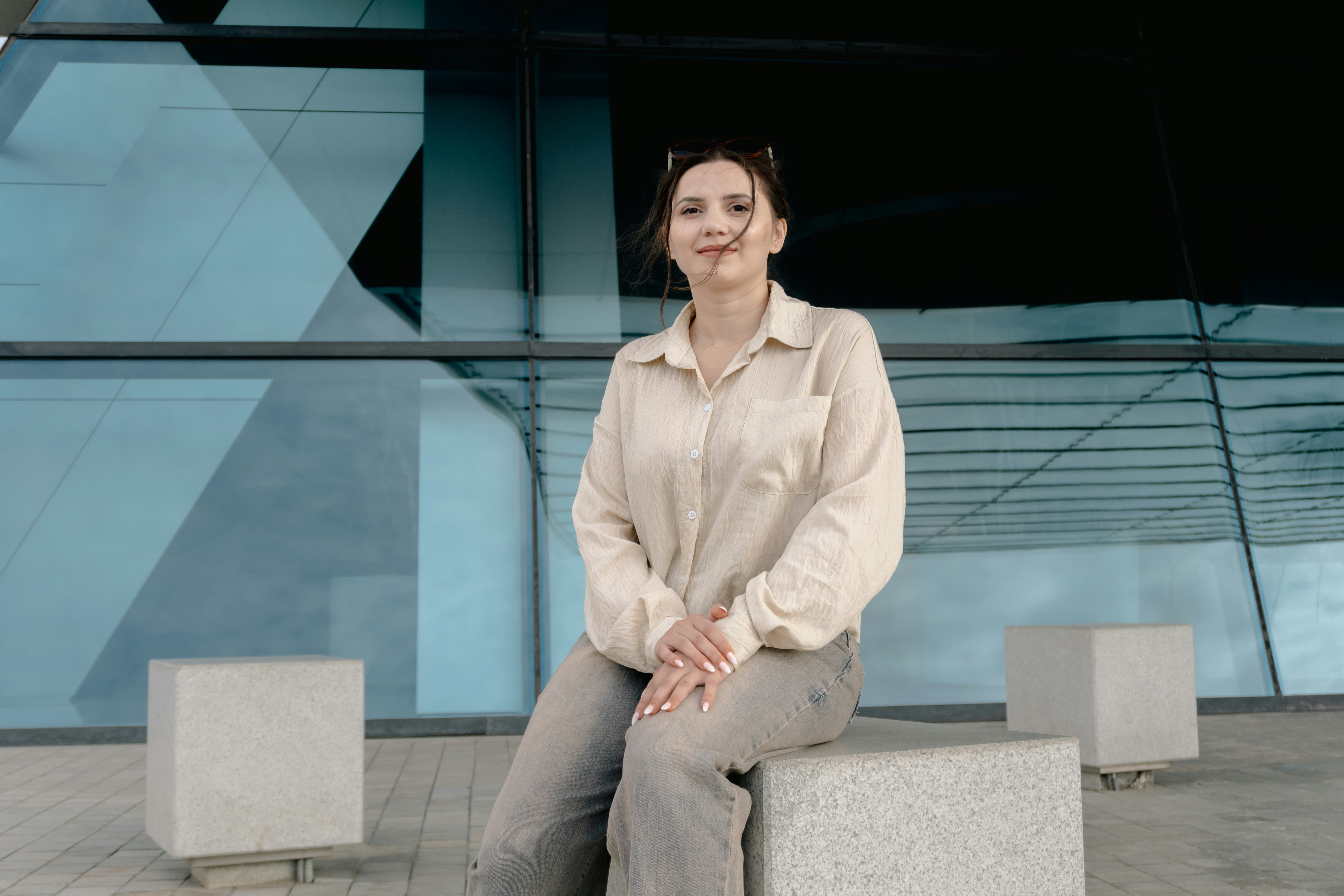 Relaxed Confidence: a woman sits on concrete blocks outside a glass-fronted building