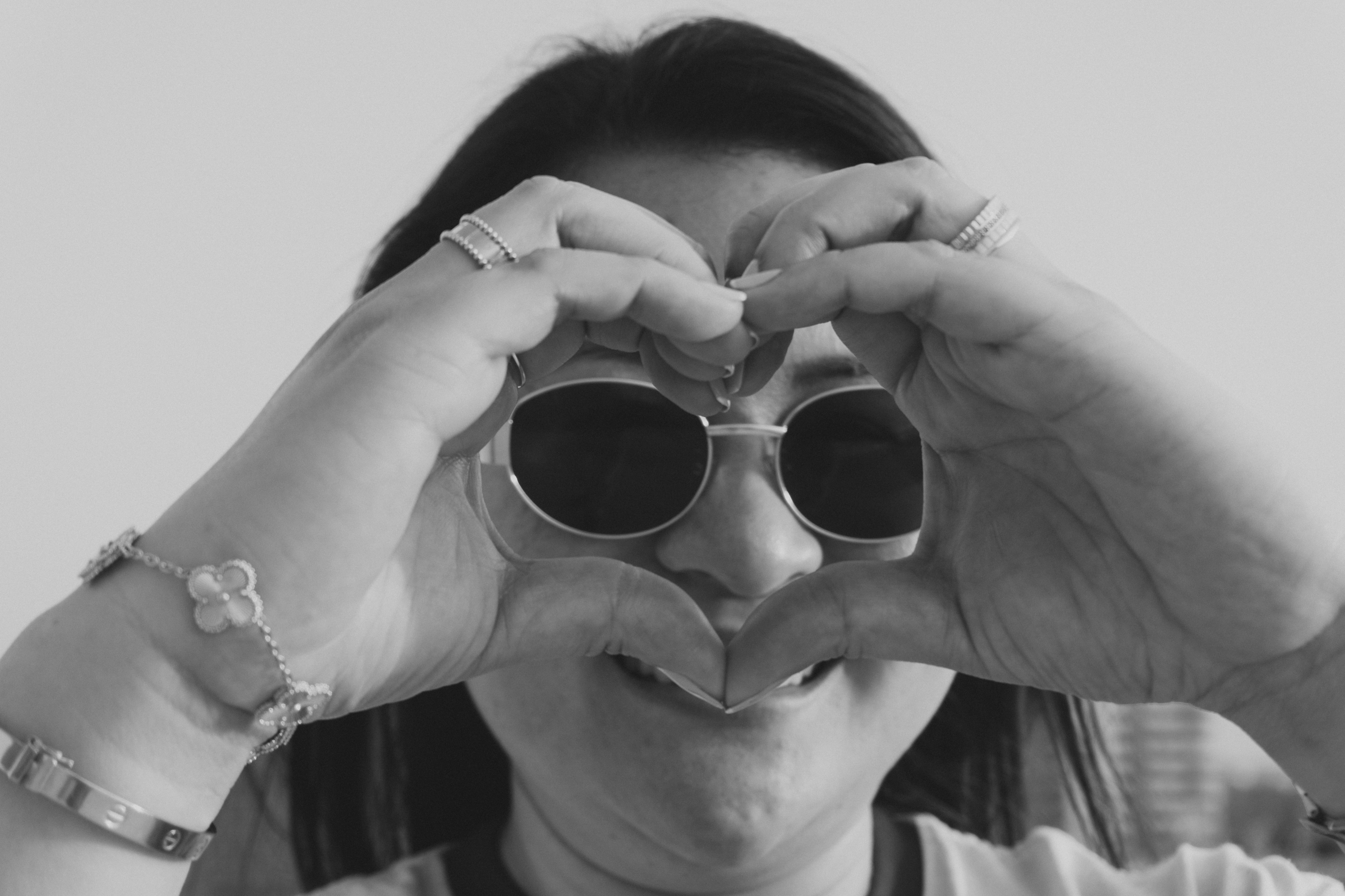 Heart in Focus: A Playful Portrait Framing with Hands and Sunglasses