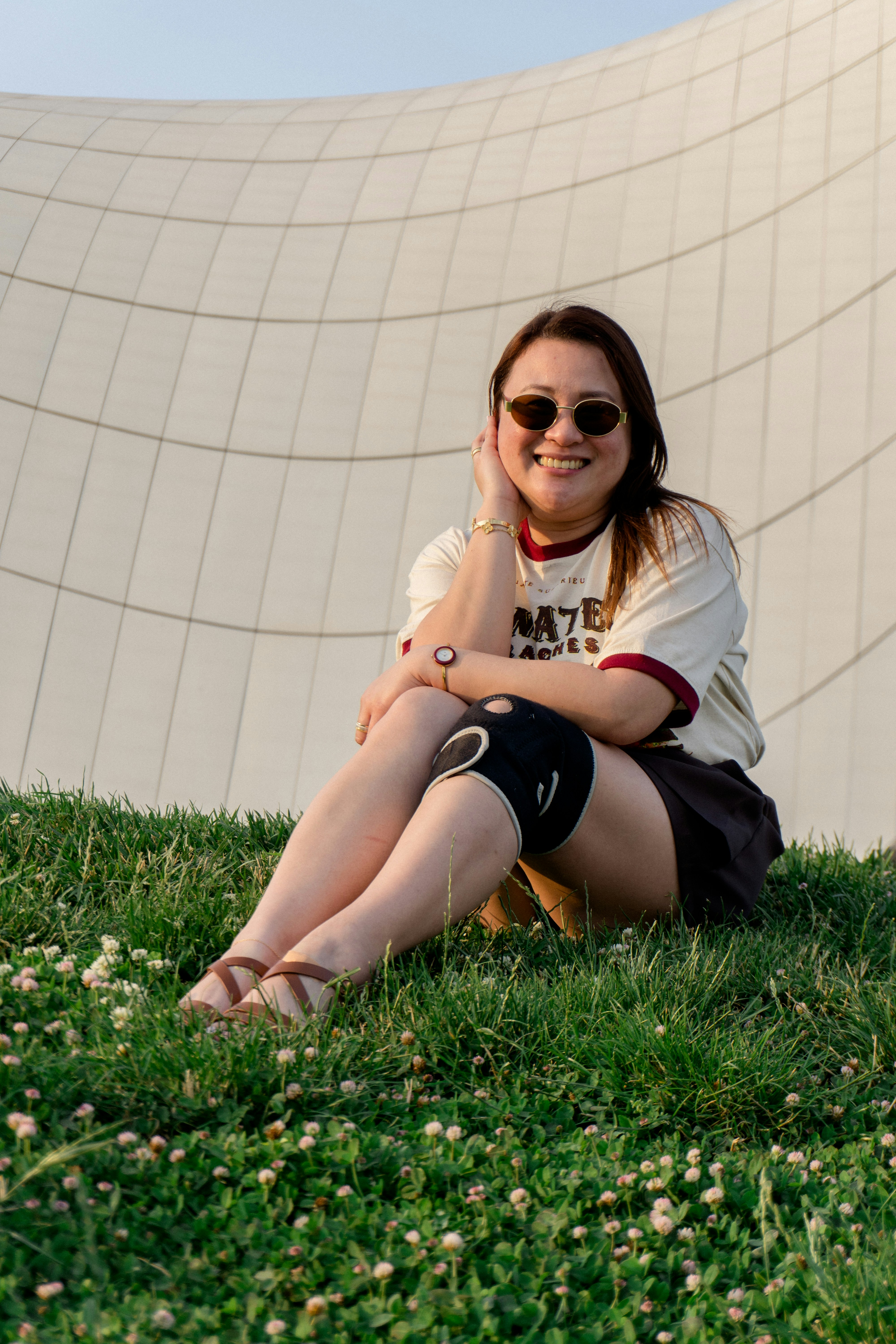 Sunlit smile on the grassy slope beneath a curved architectural wall