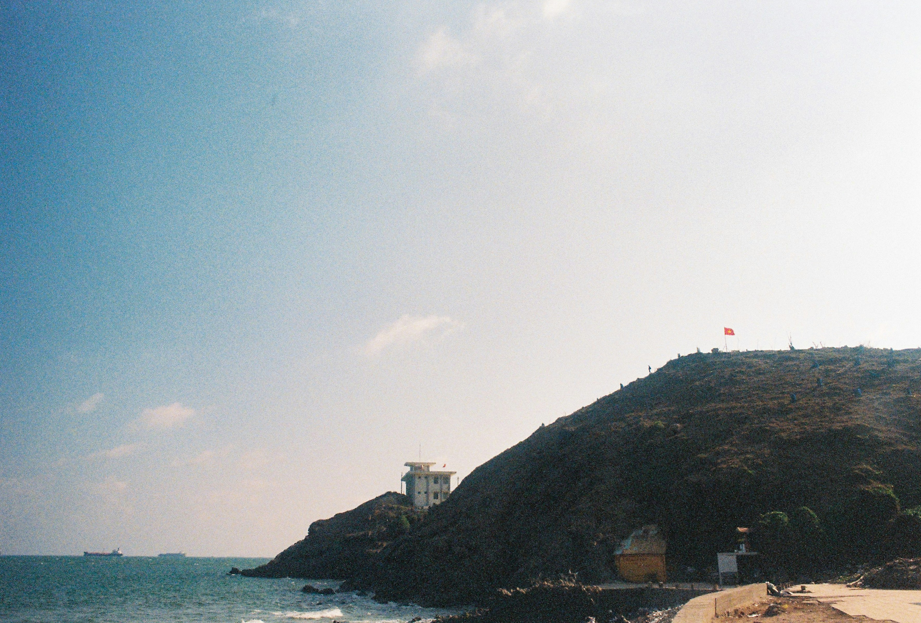 Coastal Cliff with SmallStructure and Flag under Open Sky