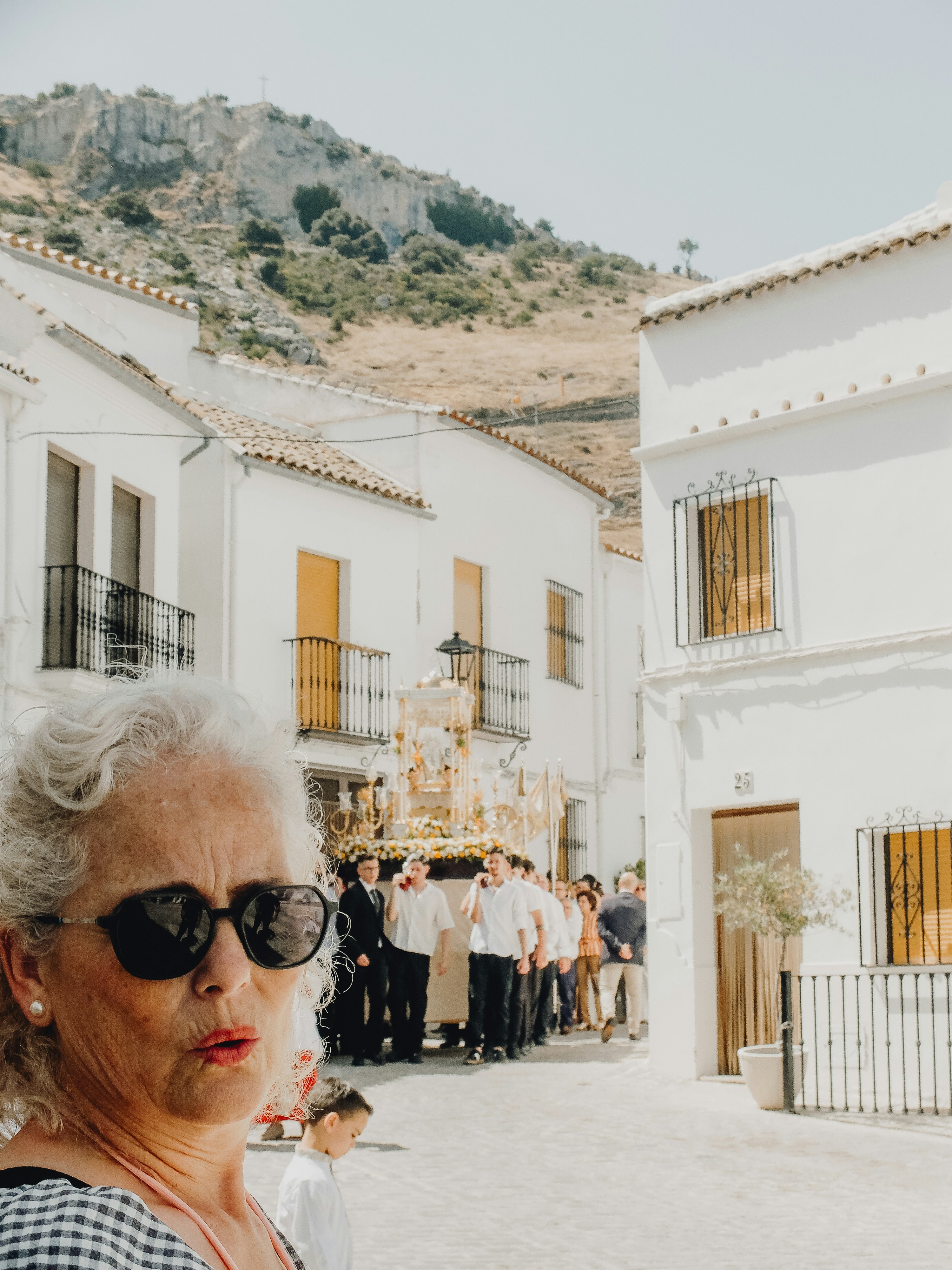 Sunlit Street Procession Framed by a Grandmother’s Gaze