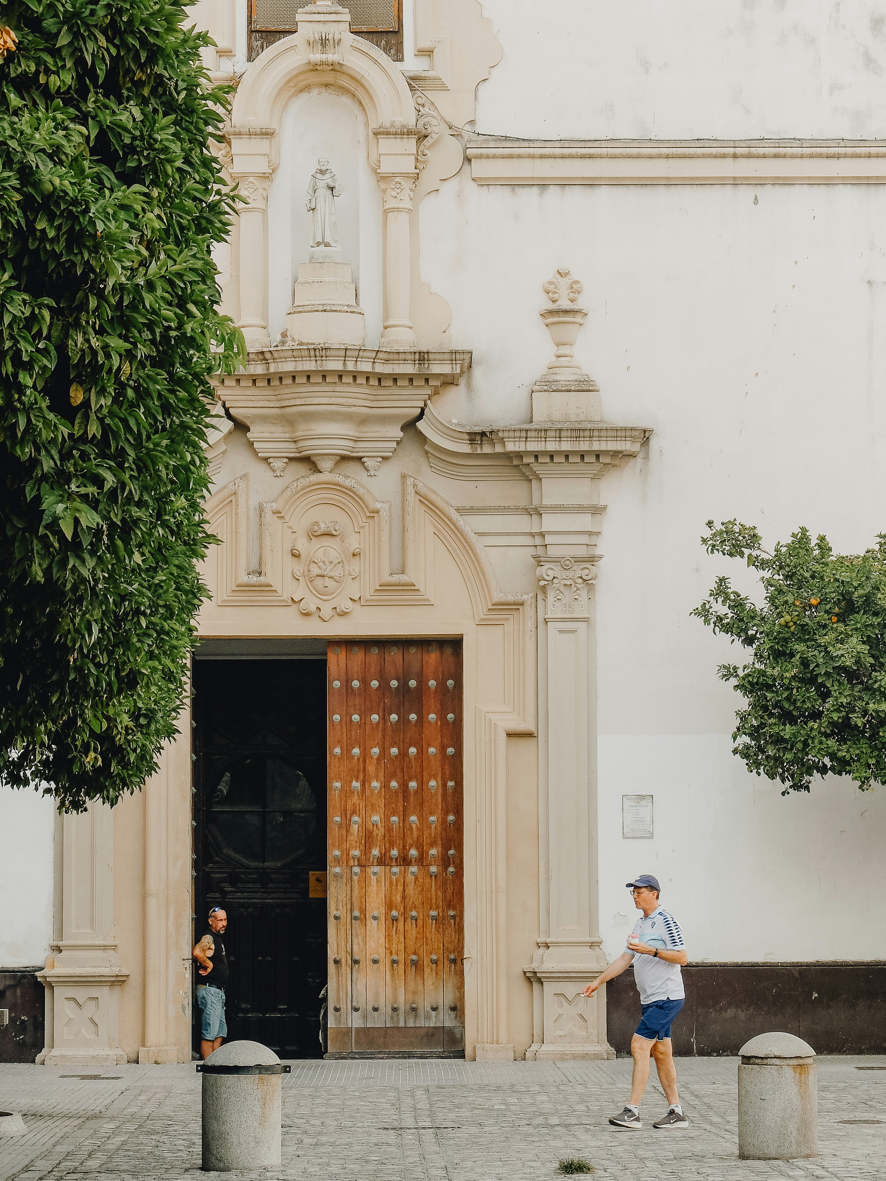 Traveler in a sunlit courtyard steps through a grand doorway