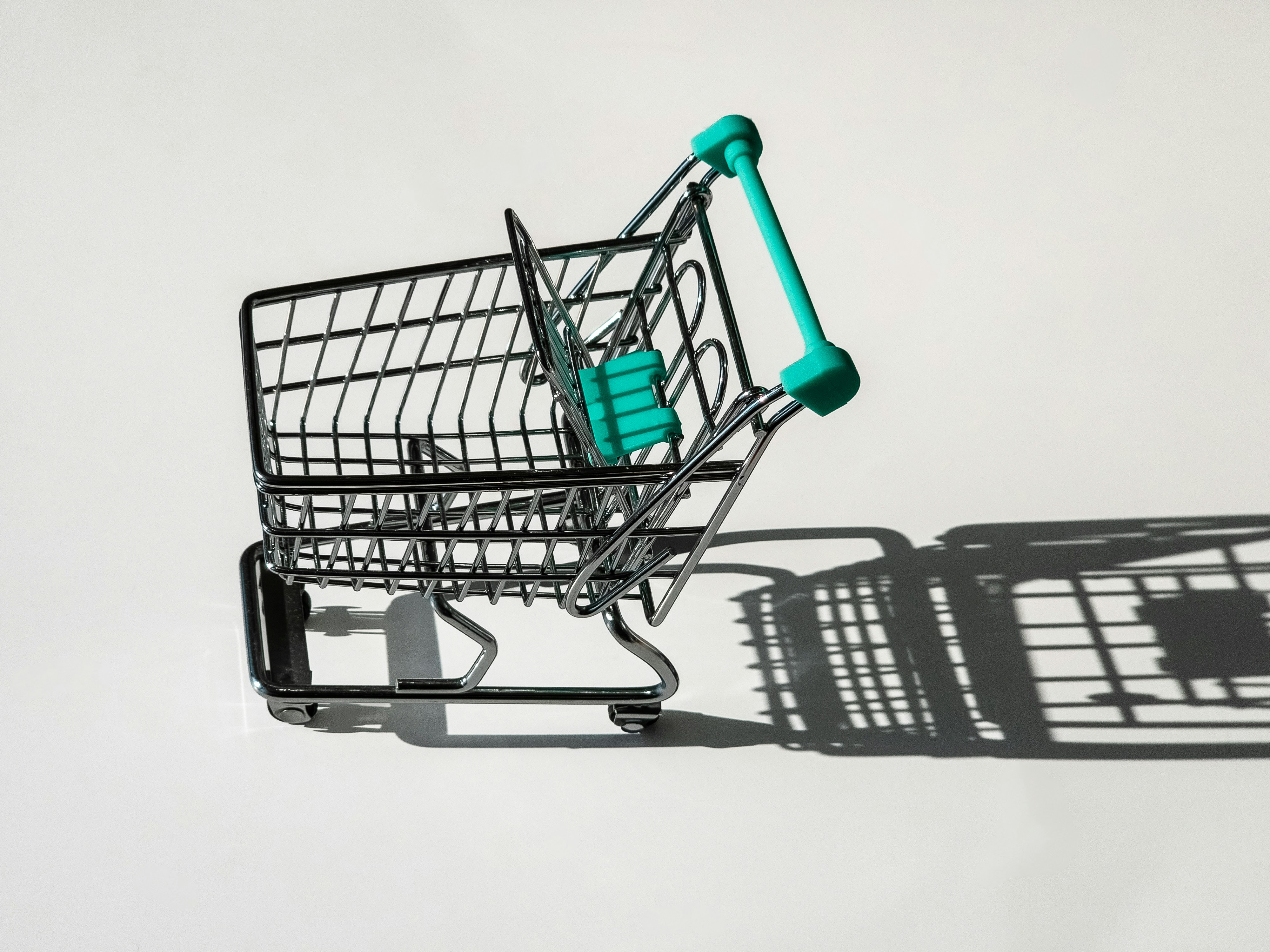 Teal-Handled Cart at Rest: Shadowed Geometry on White