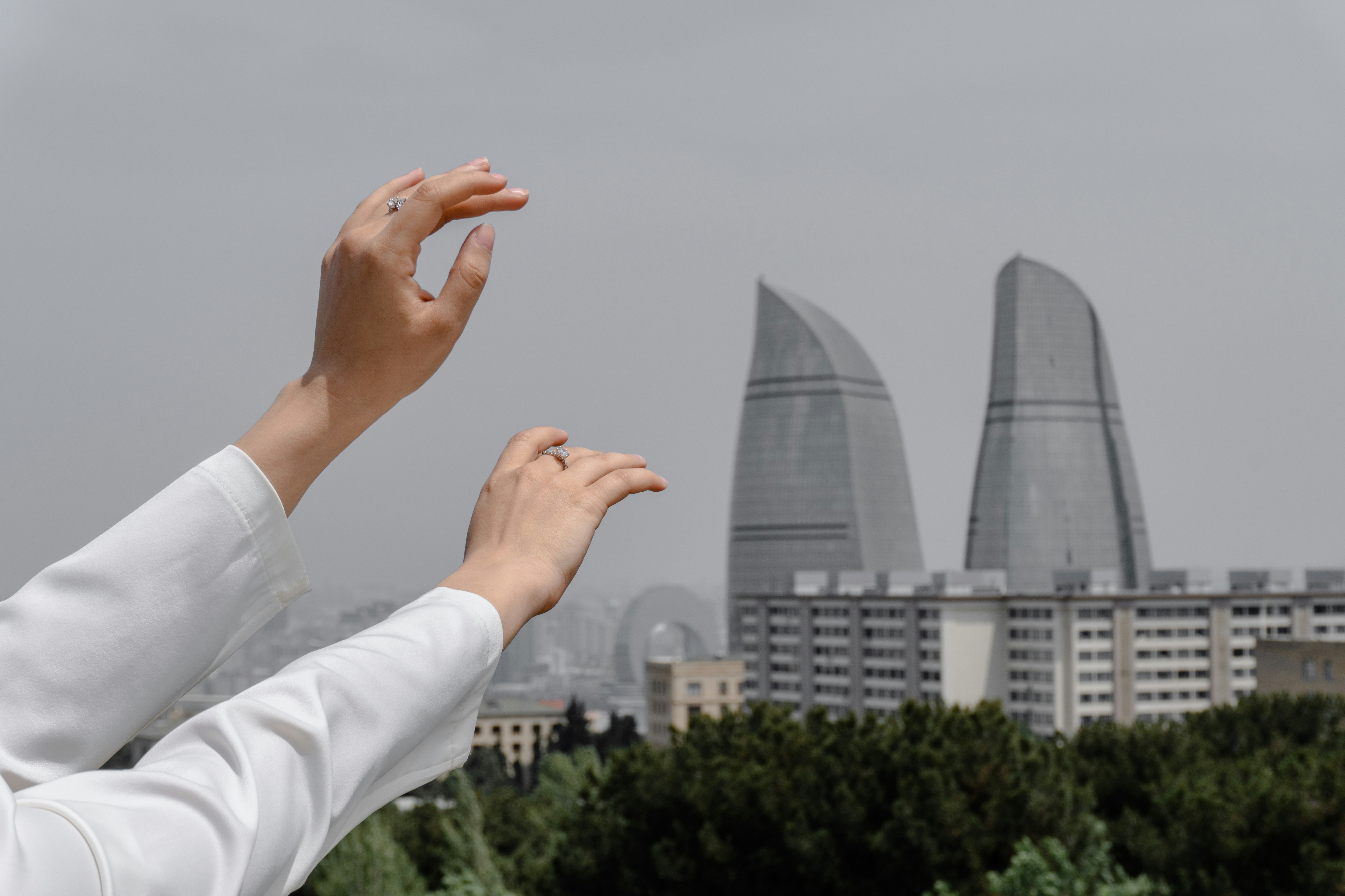 Hands Framing a Skyline: A Quiet Gesture Against Modern Towers