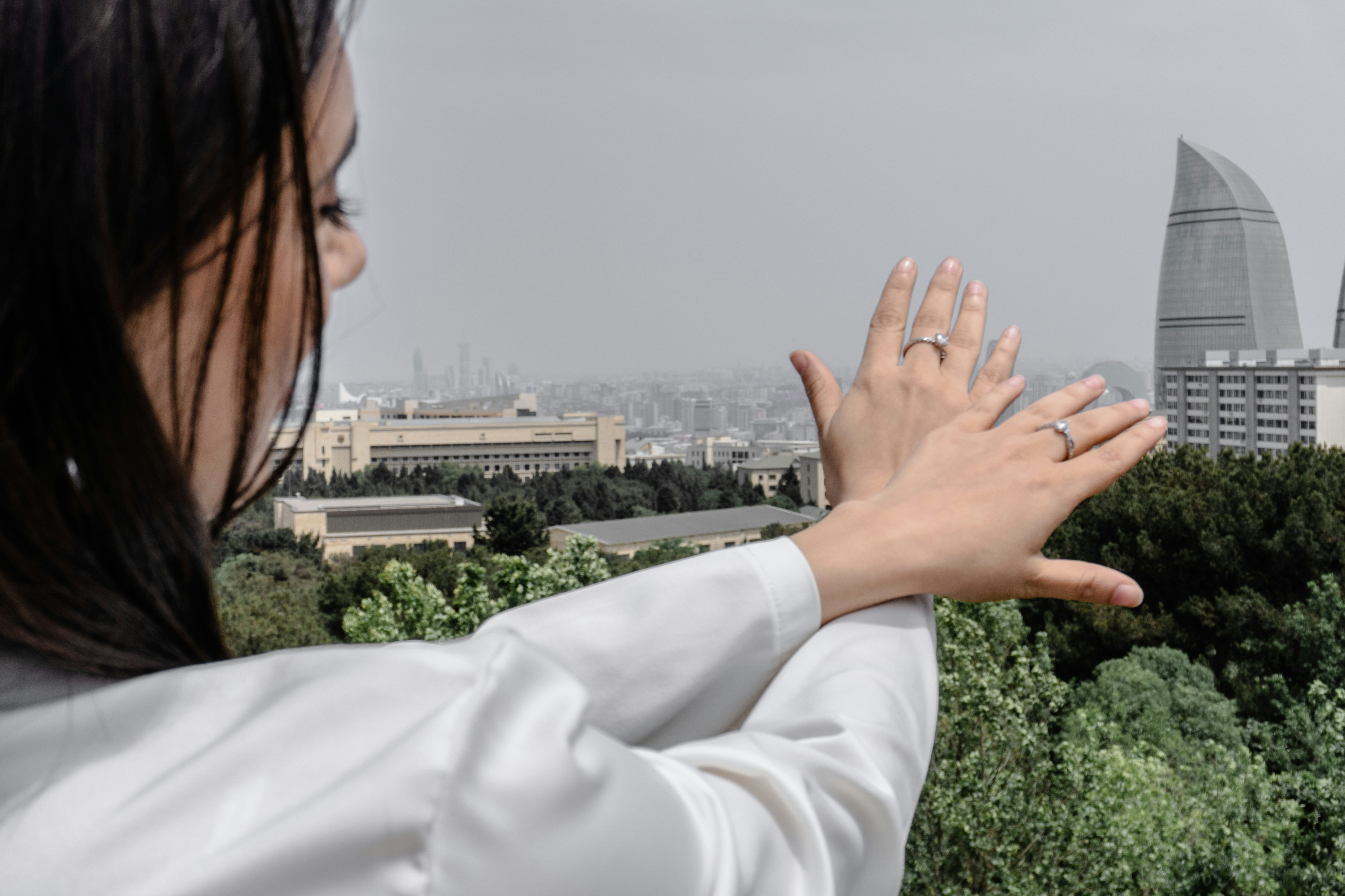 Hands Reach Toward a City Horizon Beyond Greenery