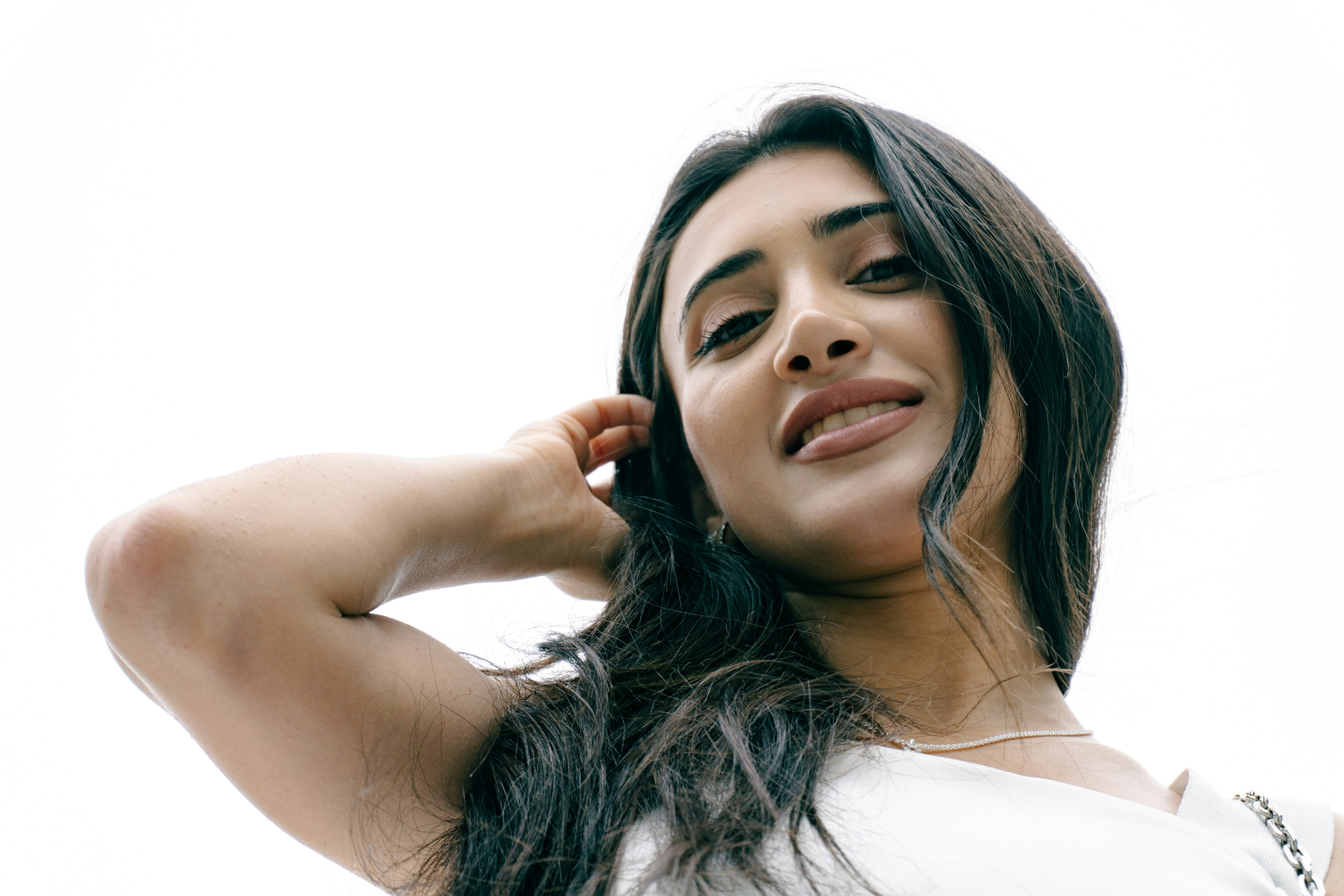 Low-angle portrait: confident smile against bright sky