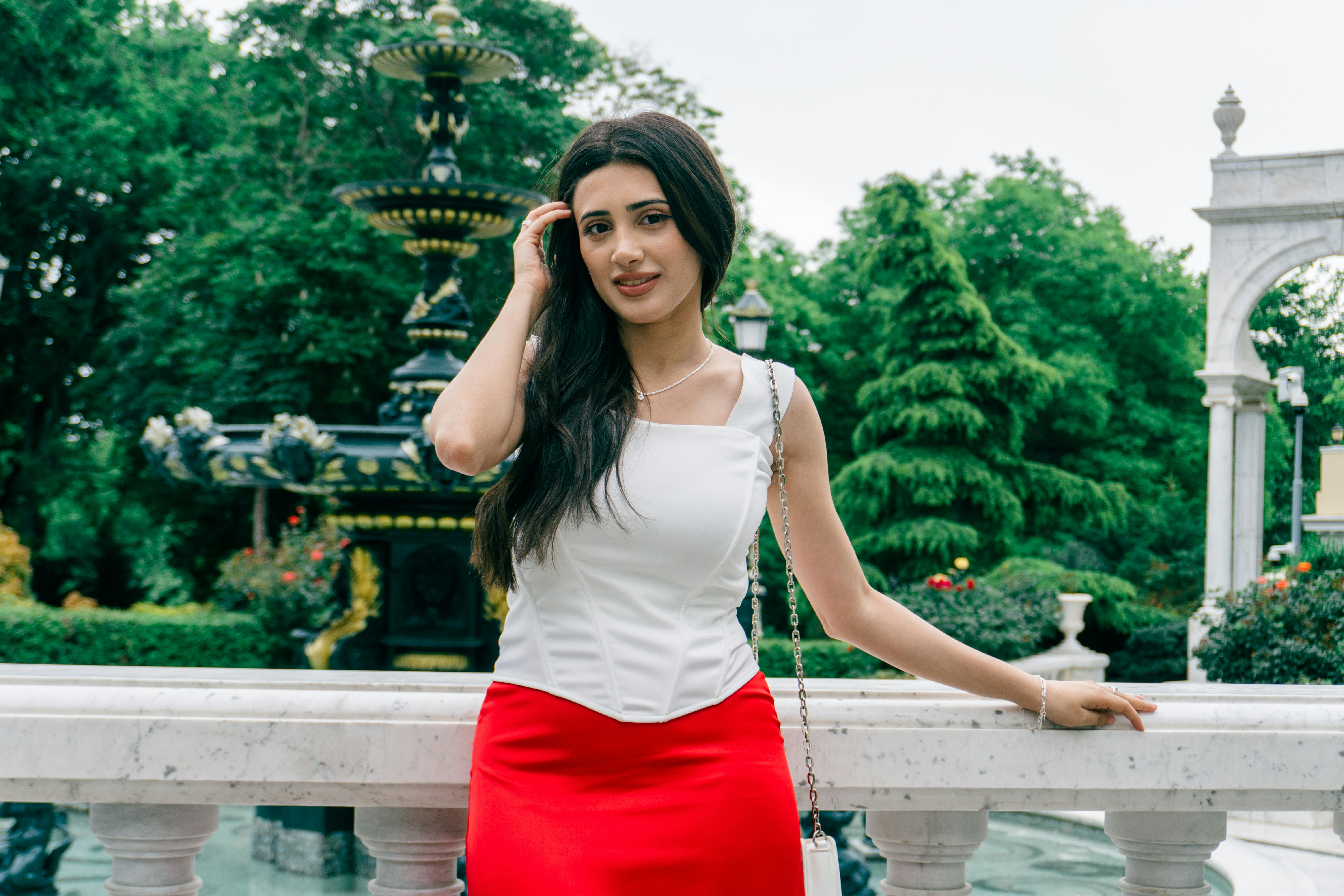 Elegant presence by the marble railing in a sunlit garden