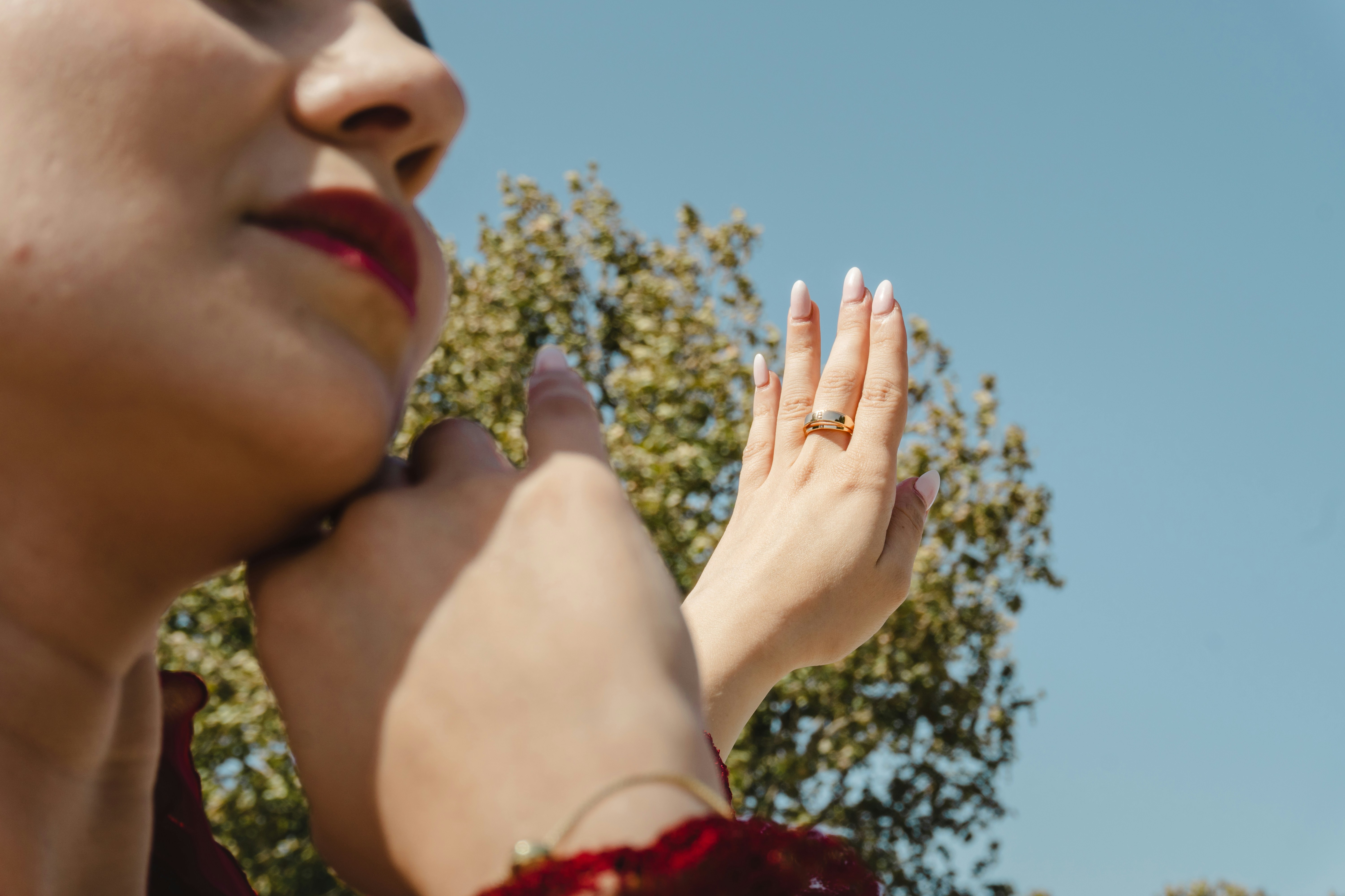Gesture in Focus: A Close-Up of Hands and Profile Against a Clear Sky